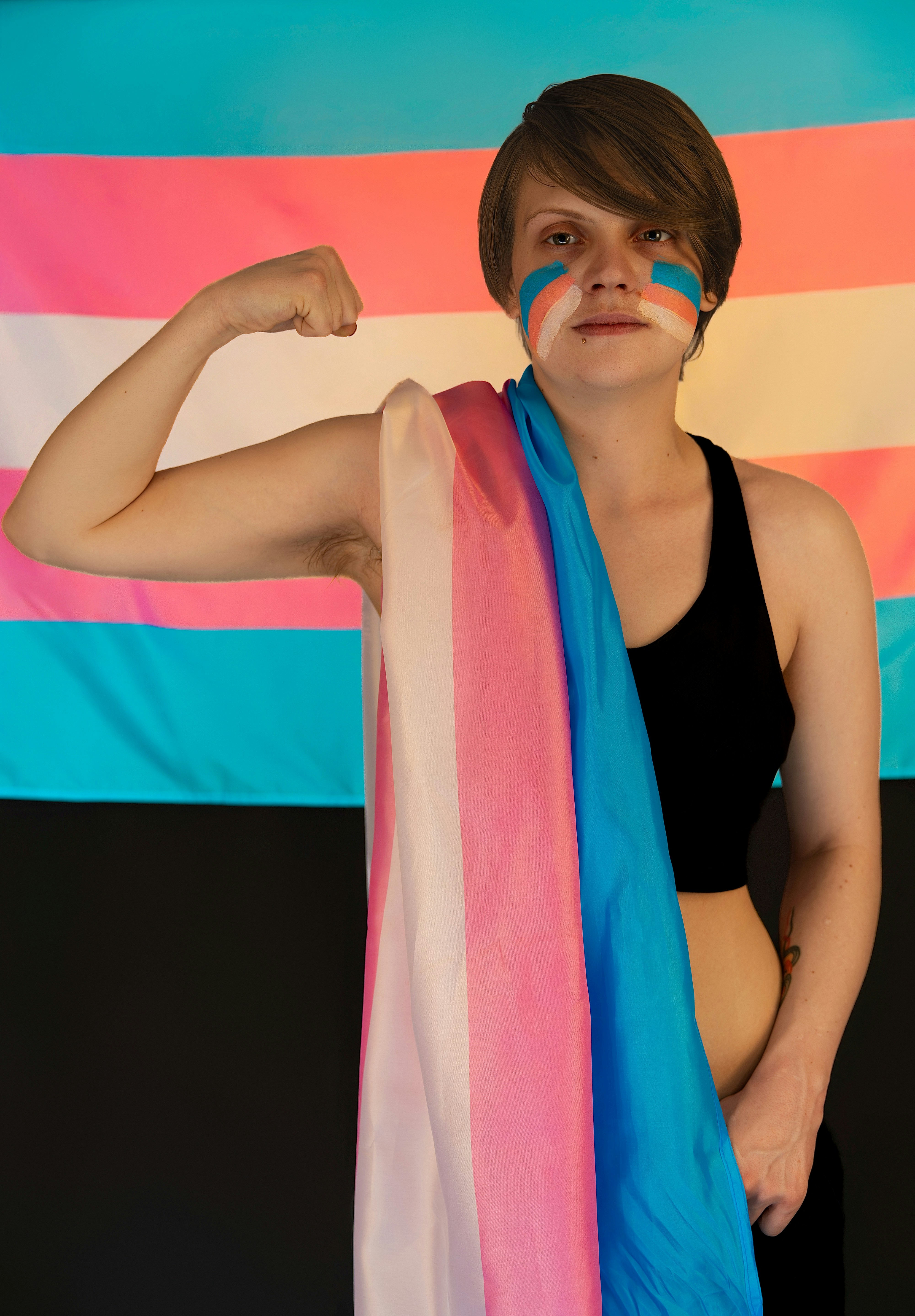 Portrait of Pride: A Defiant Pose Against Colorful Pride Flag Backdrop