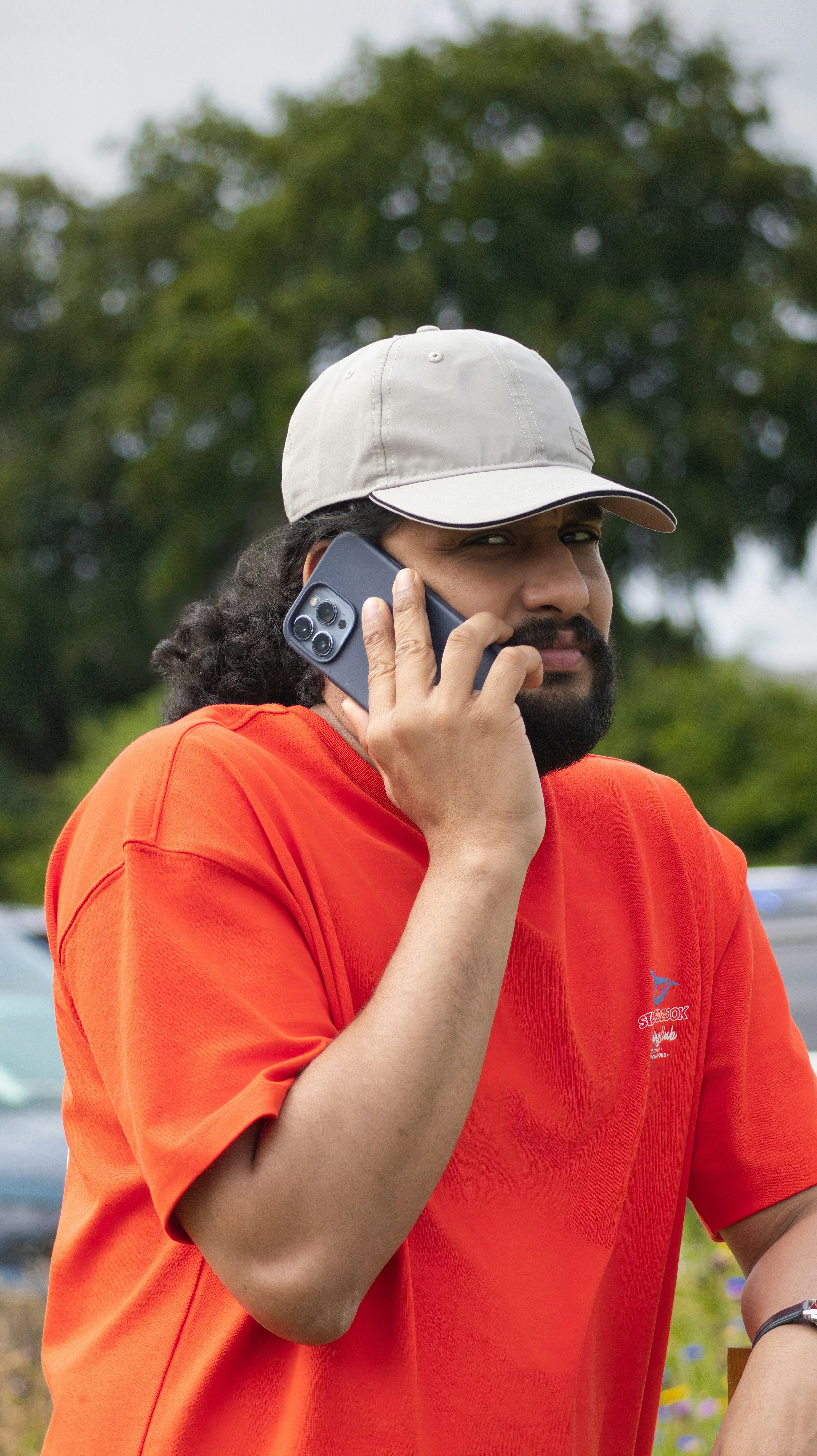 Phone in hand, cap shade, and a sunlit smile: casual portrait in a parking lot