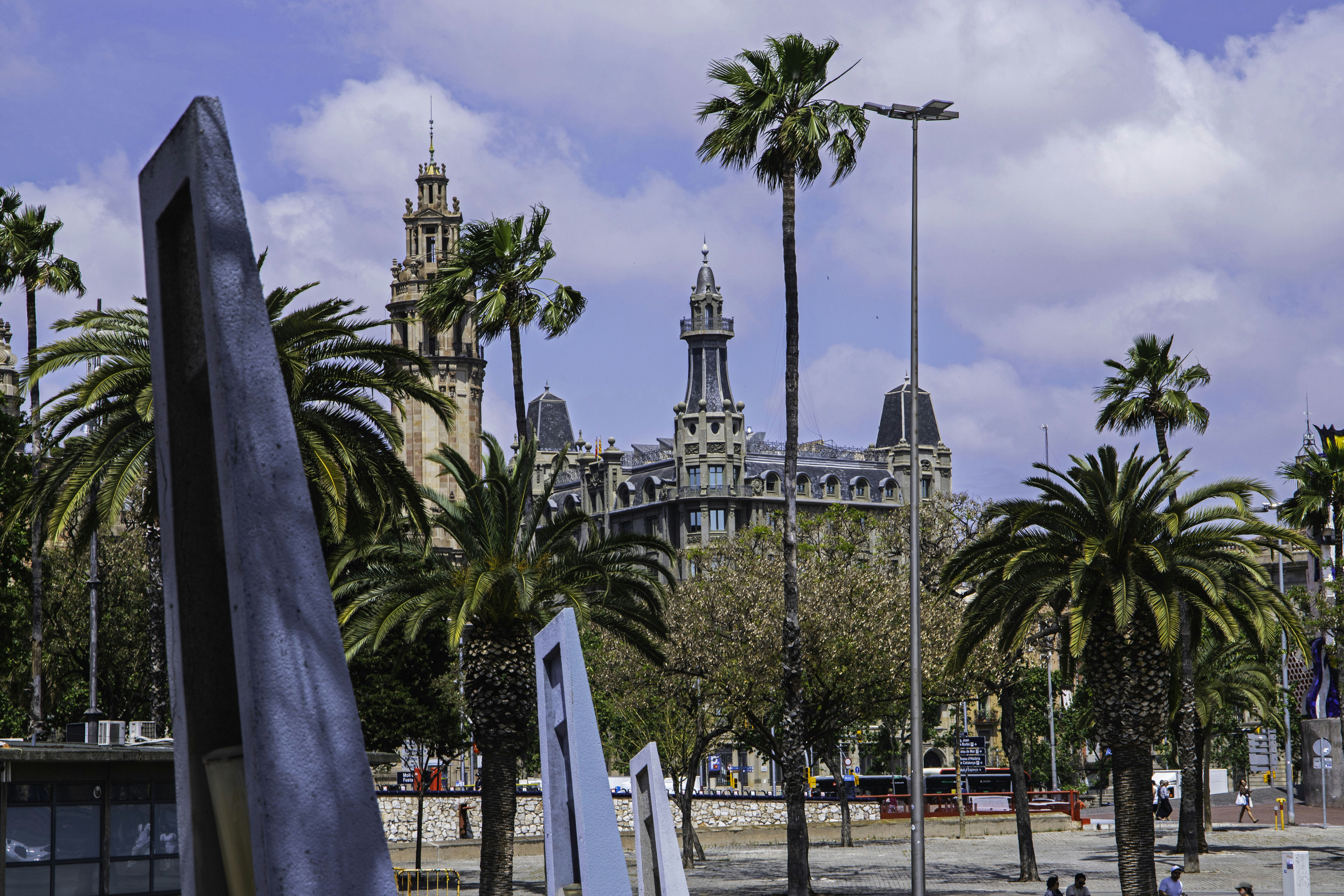 Palm-lined quay with sculptural obelisks and historic towers