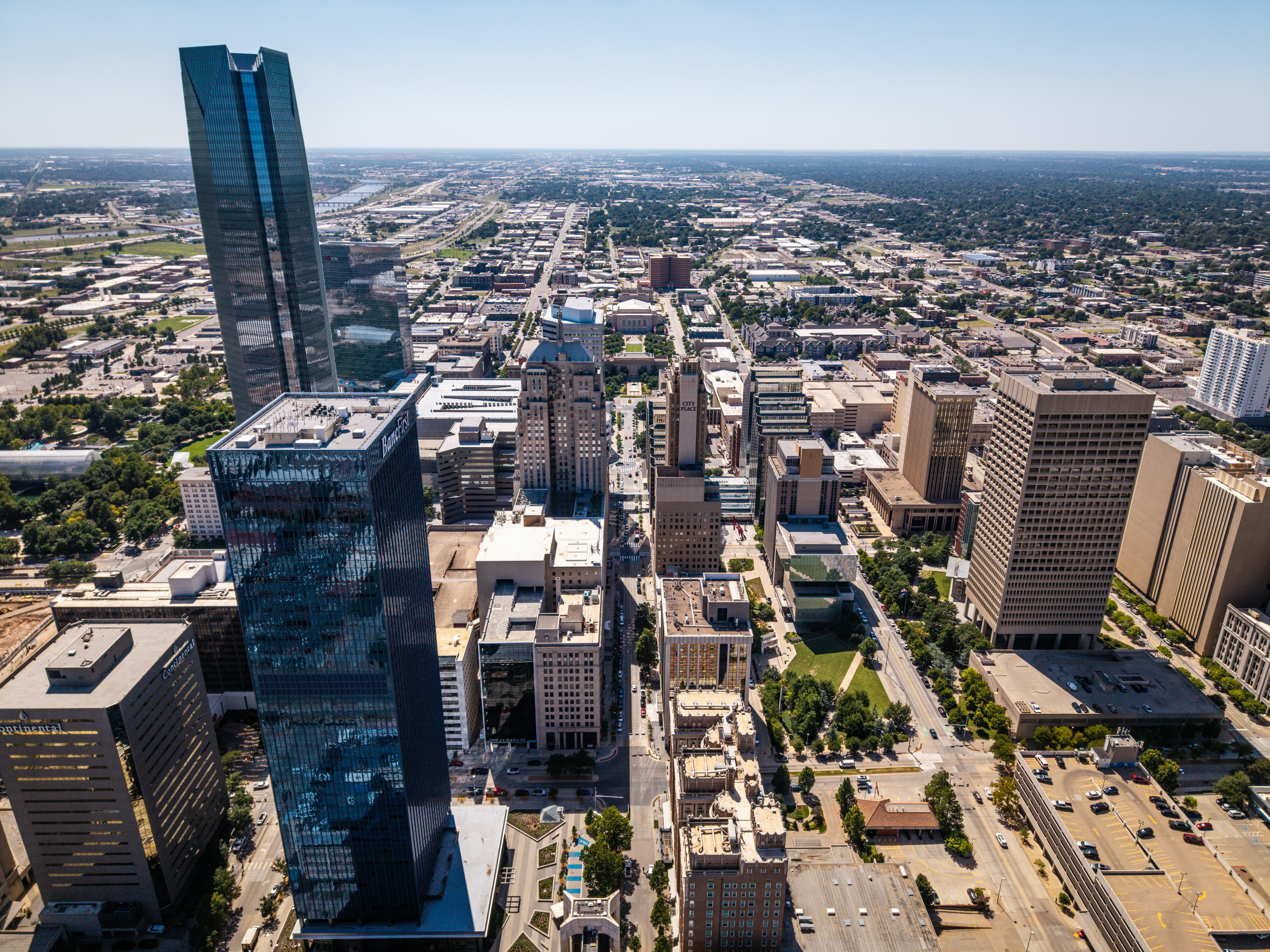 Aerial view of a dense downtown with tall glass towers and a grid of streets beneath, capturing the urban tapestry from above. This is a cityscape photograph.
