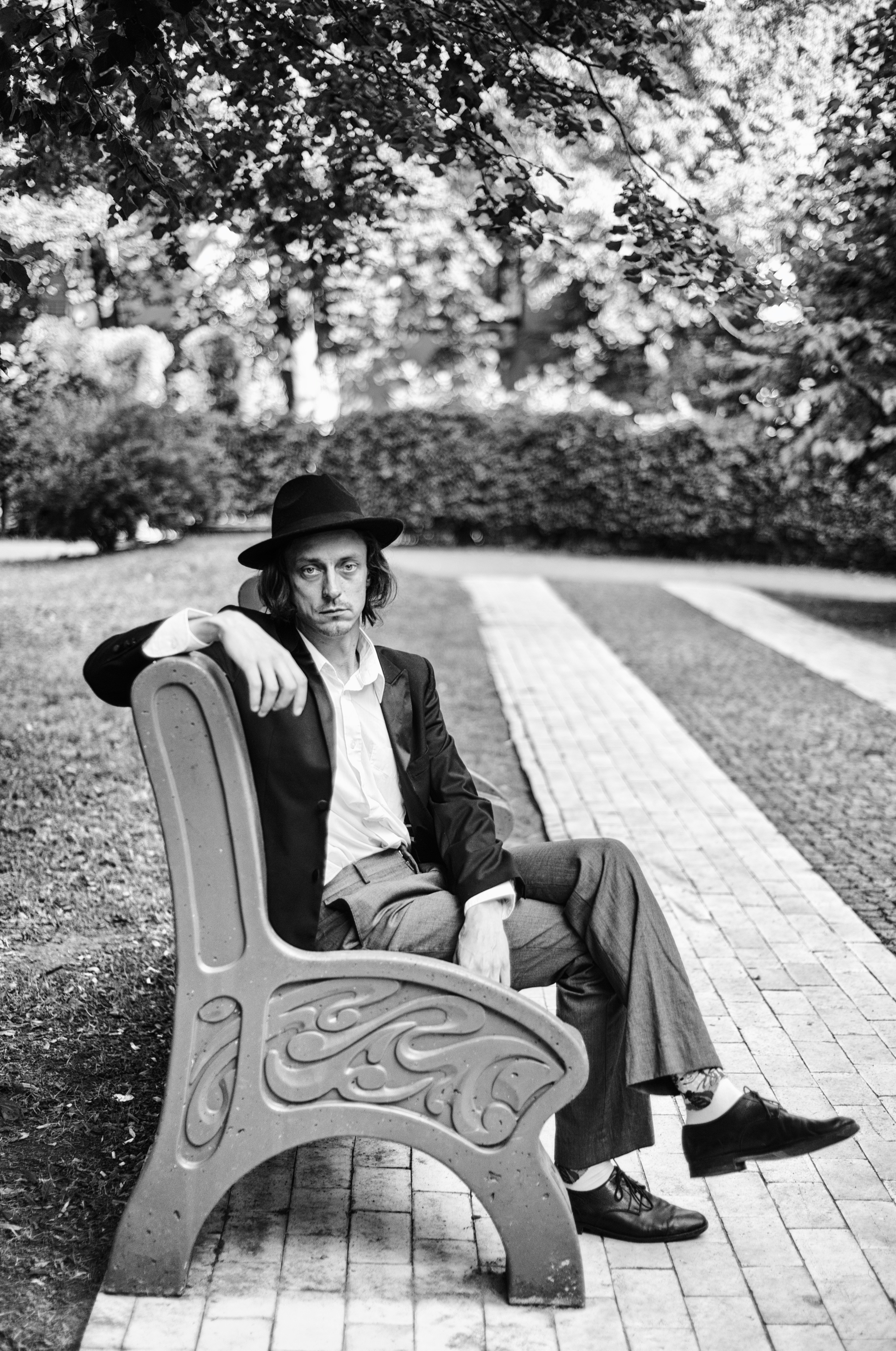 Man in a Classic Suit on a Curved Bench in a Quiet Park