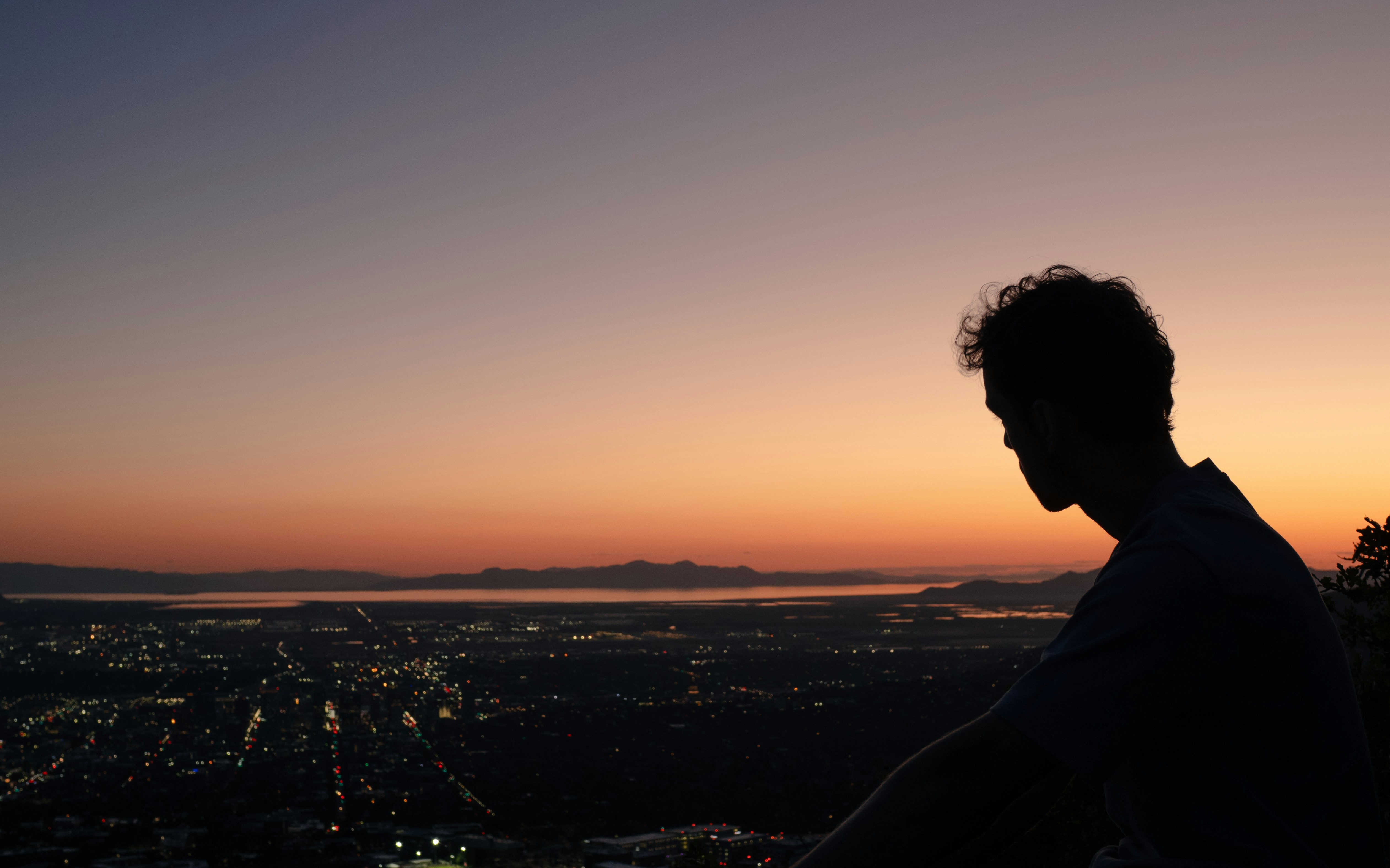 Silhouette at Dusk: A Quiet Moment Above the City Lights