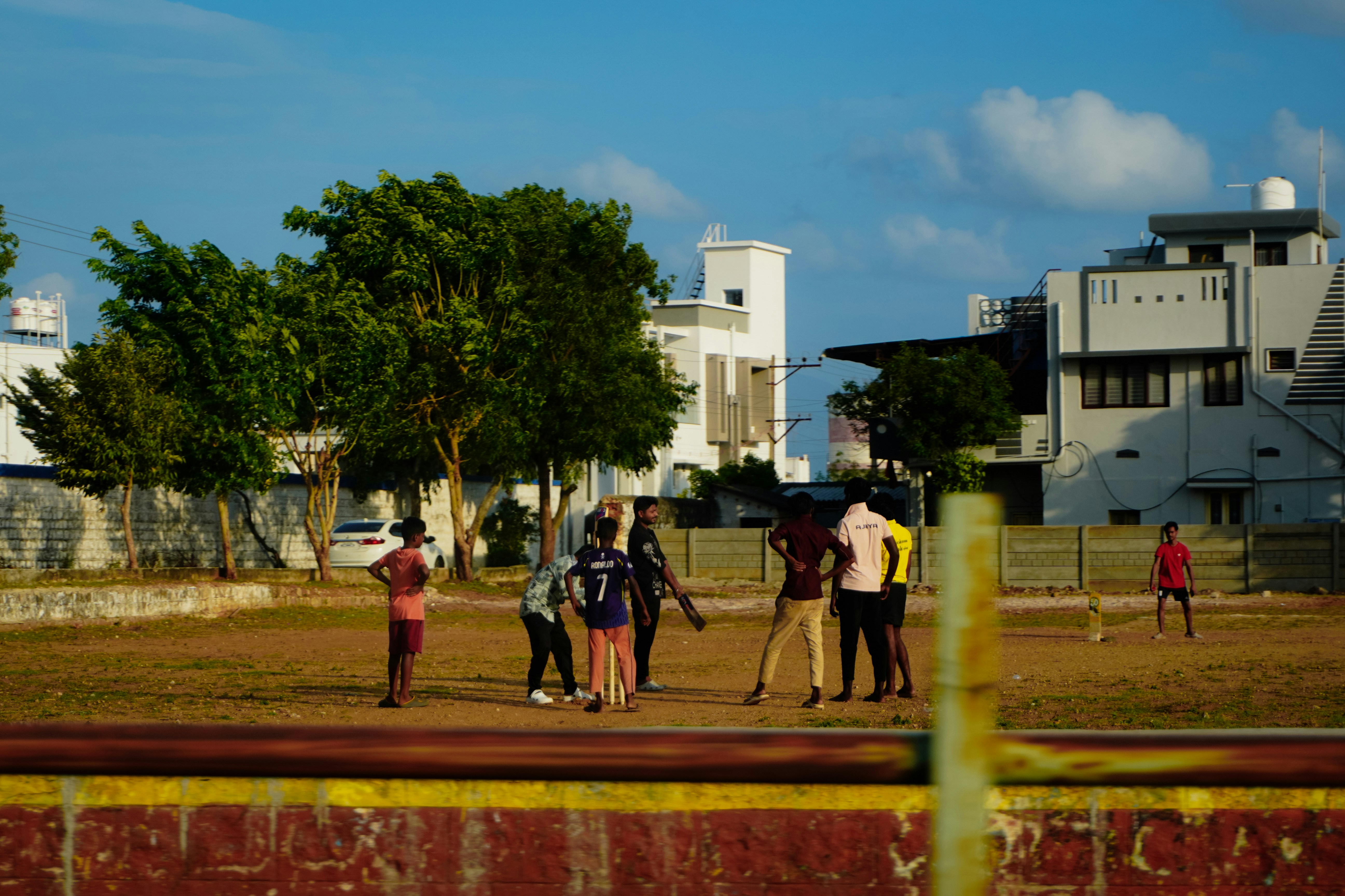 Group of youths in a sunlit field near urban buildings