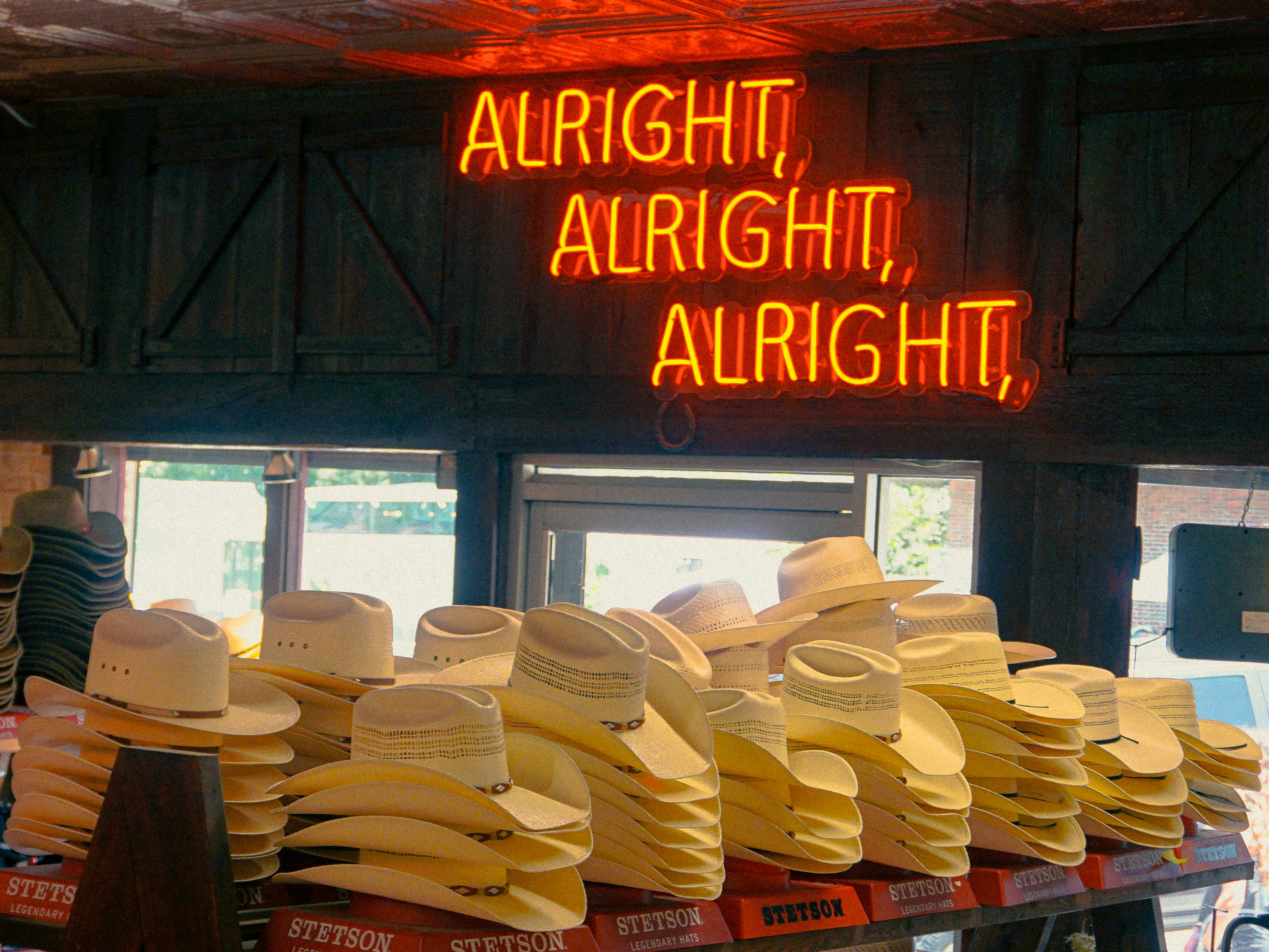 Neon Sign Over a Heap of Straw Hats