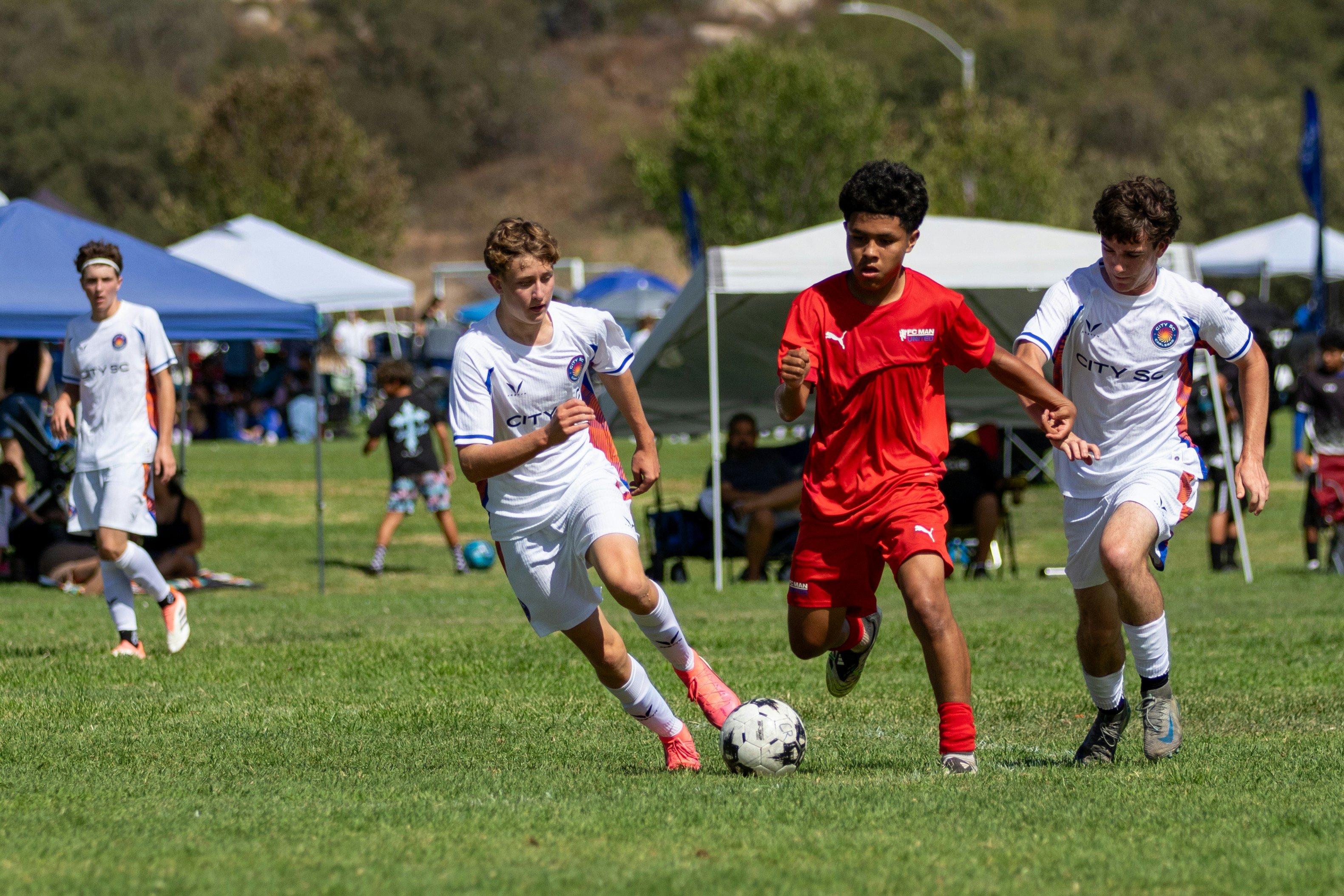 Red-jersey midfielder breaks through white-shirt rivals for the ball