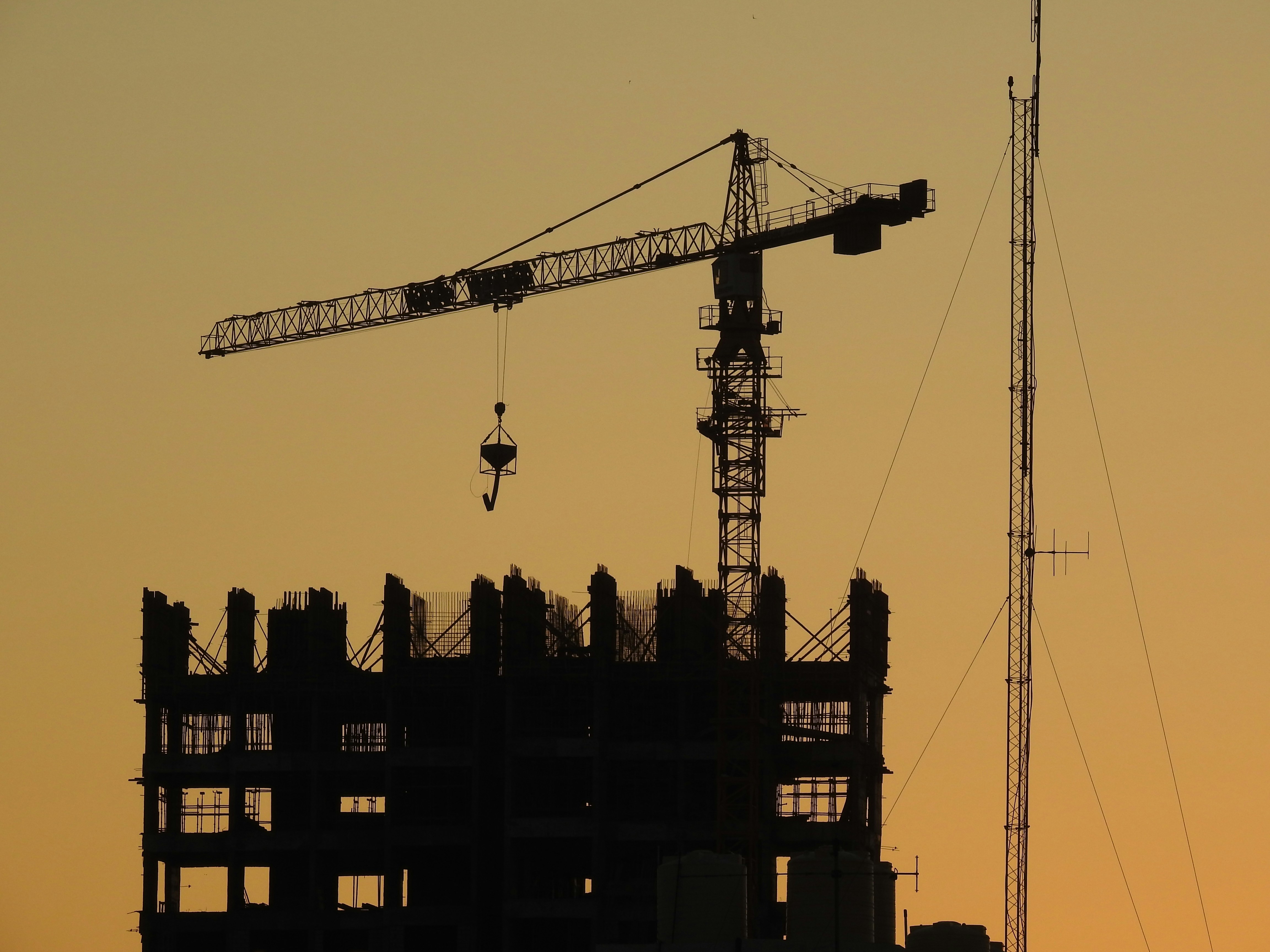 Rising Silence: Concrete Skeletons and a Distant Crane at Dusk