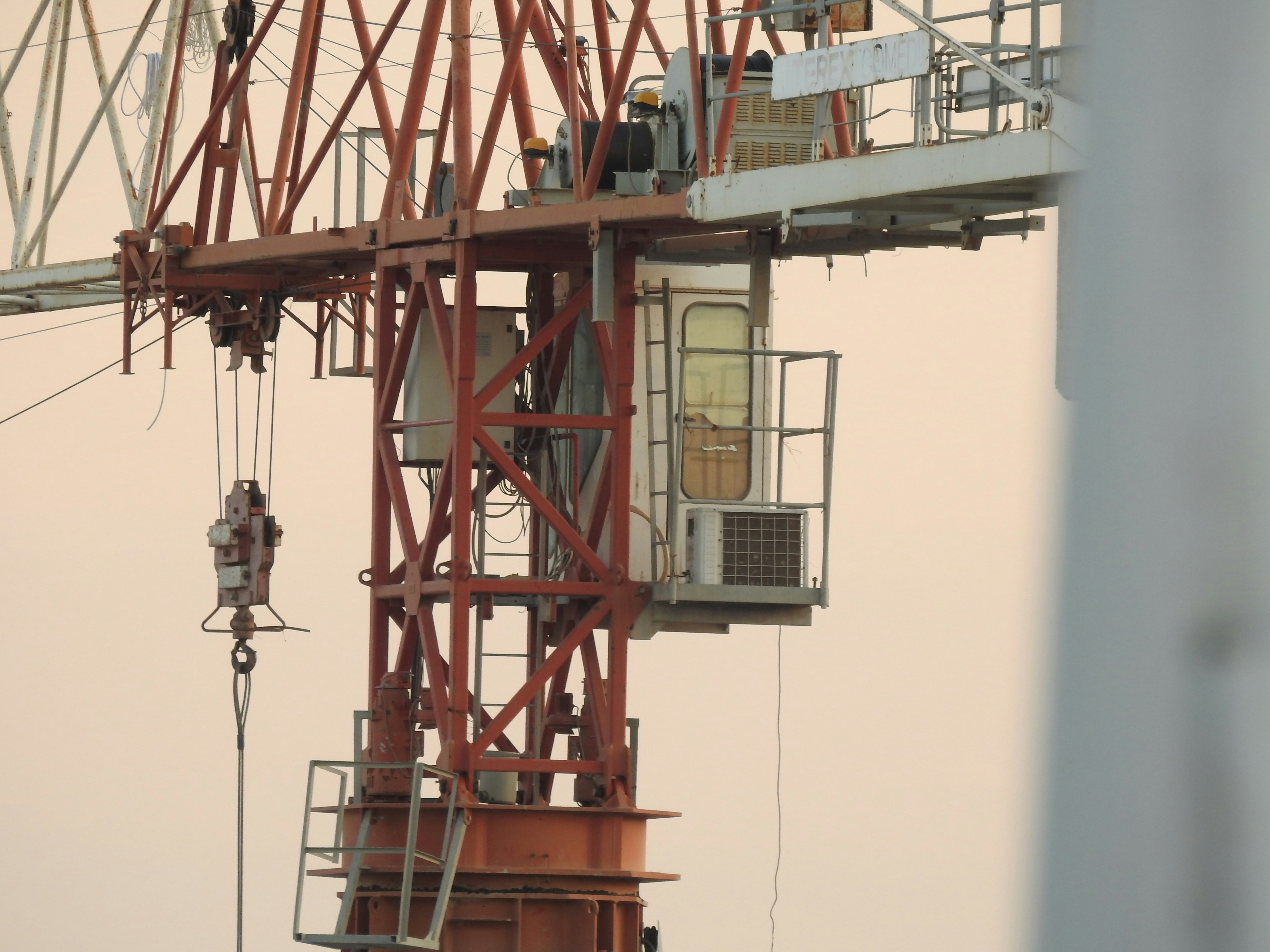 Crane Geometry: A Worker Seated Among Red Trusses