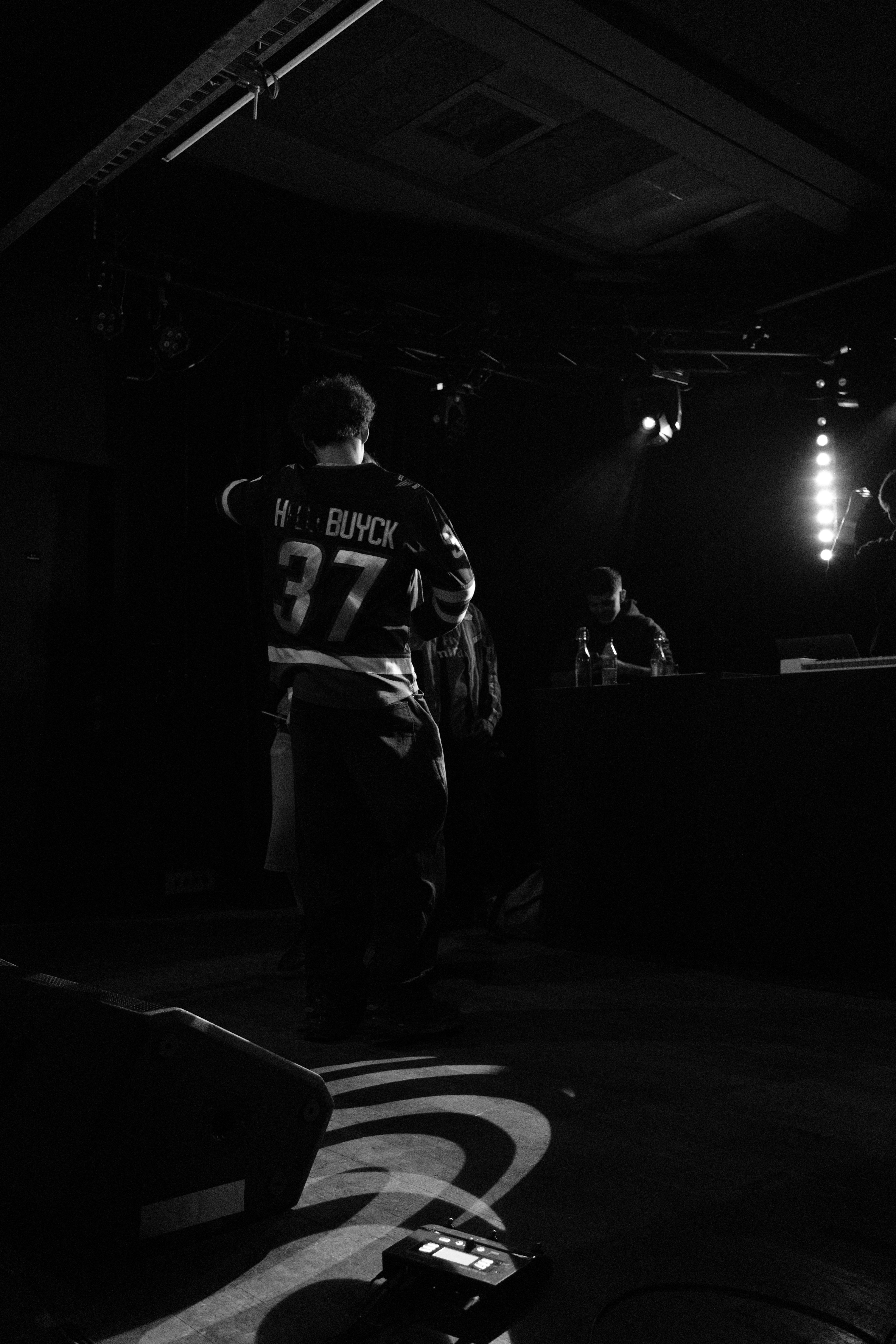 Backstage silhouette: a hockey player prepares for the spotlight on a dimly lit stage