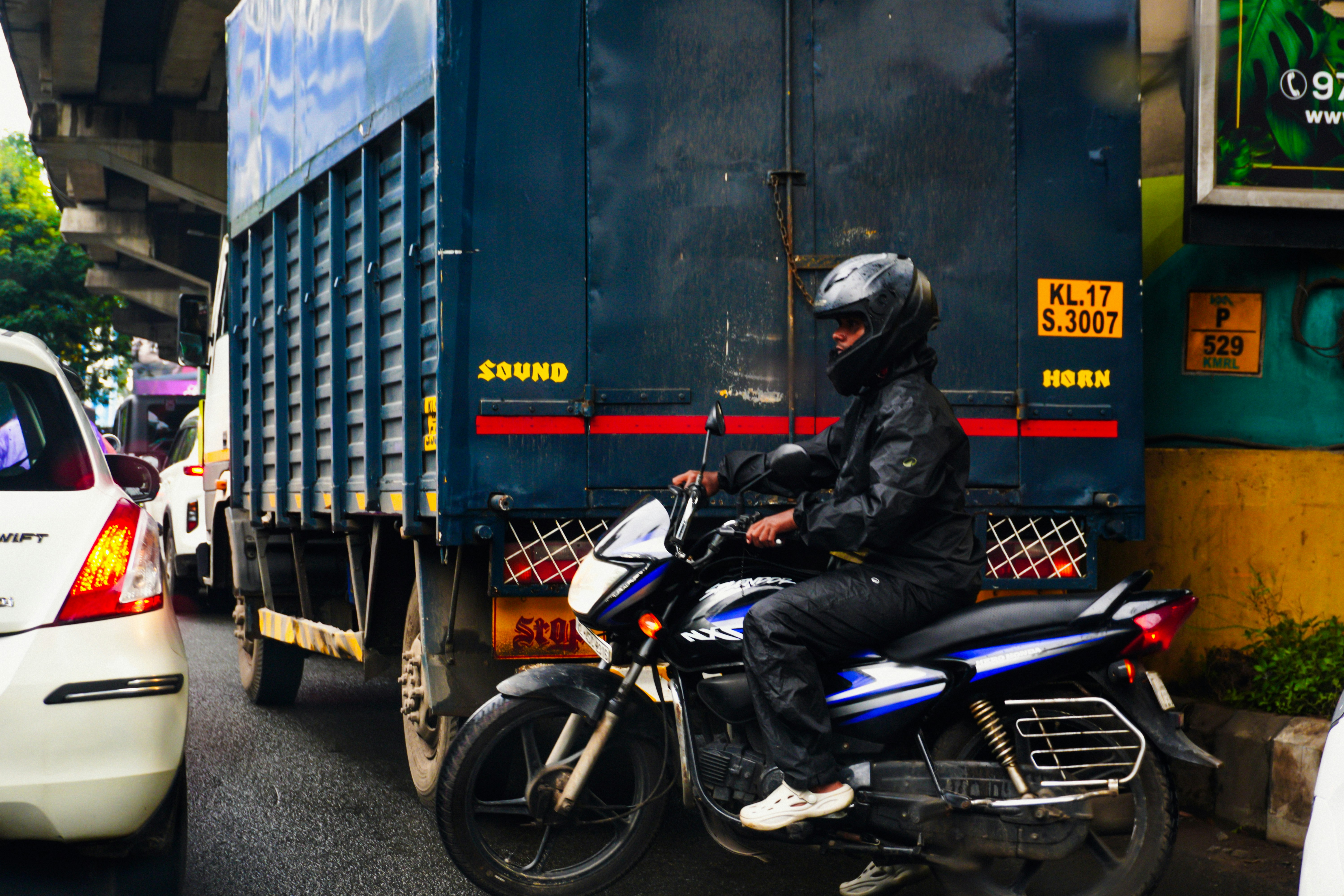 Rush Hour Relay: Rider Navigates a Narrow Gap Between Truck and Car