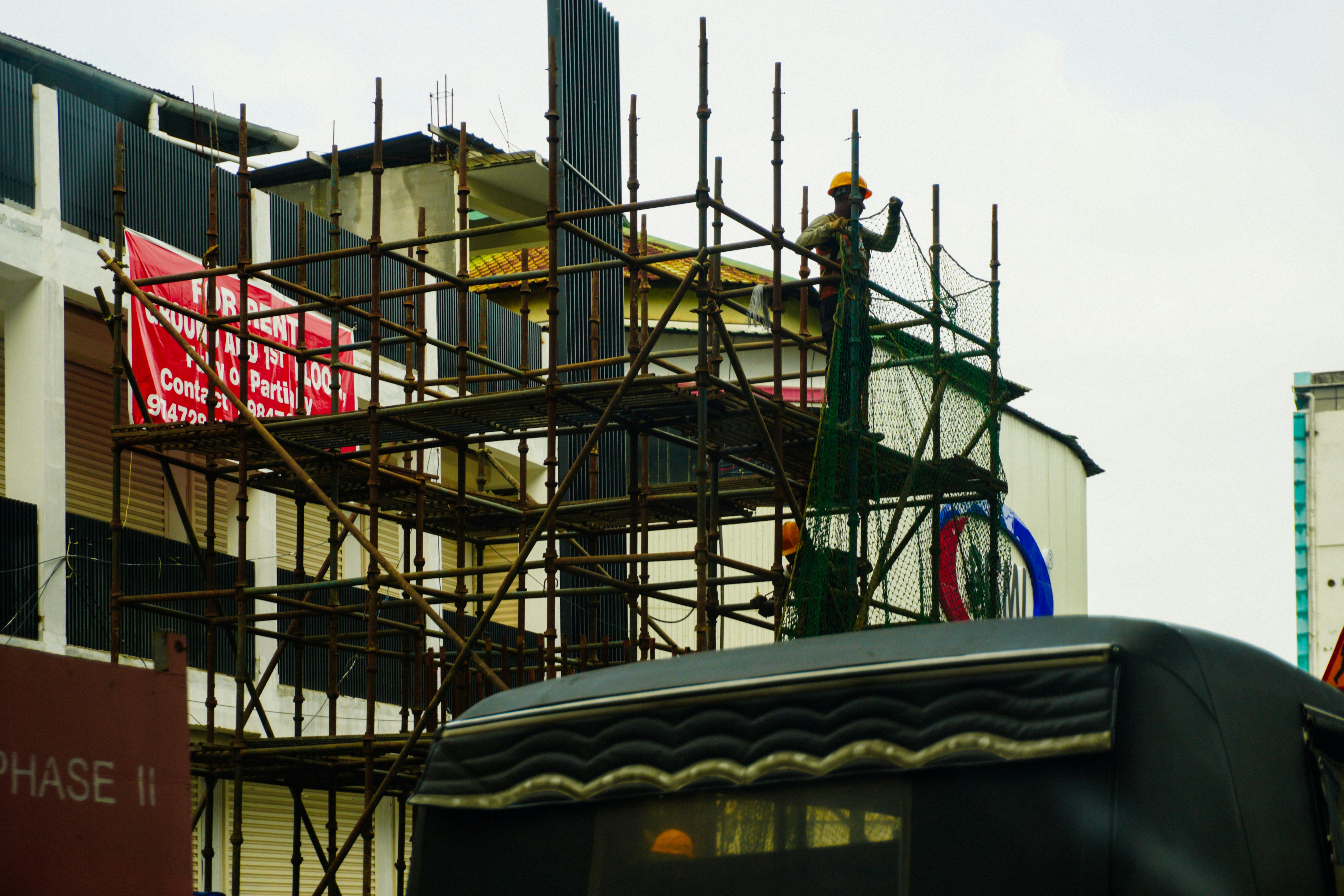 Scaffolding and construction dancer above a city bus
