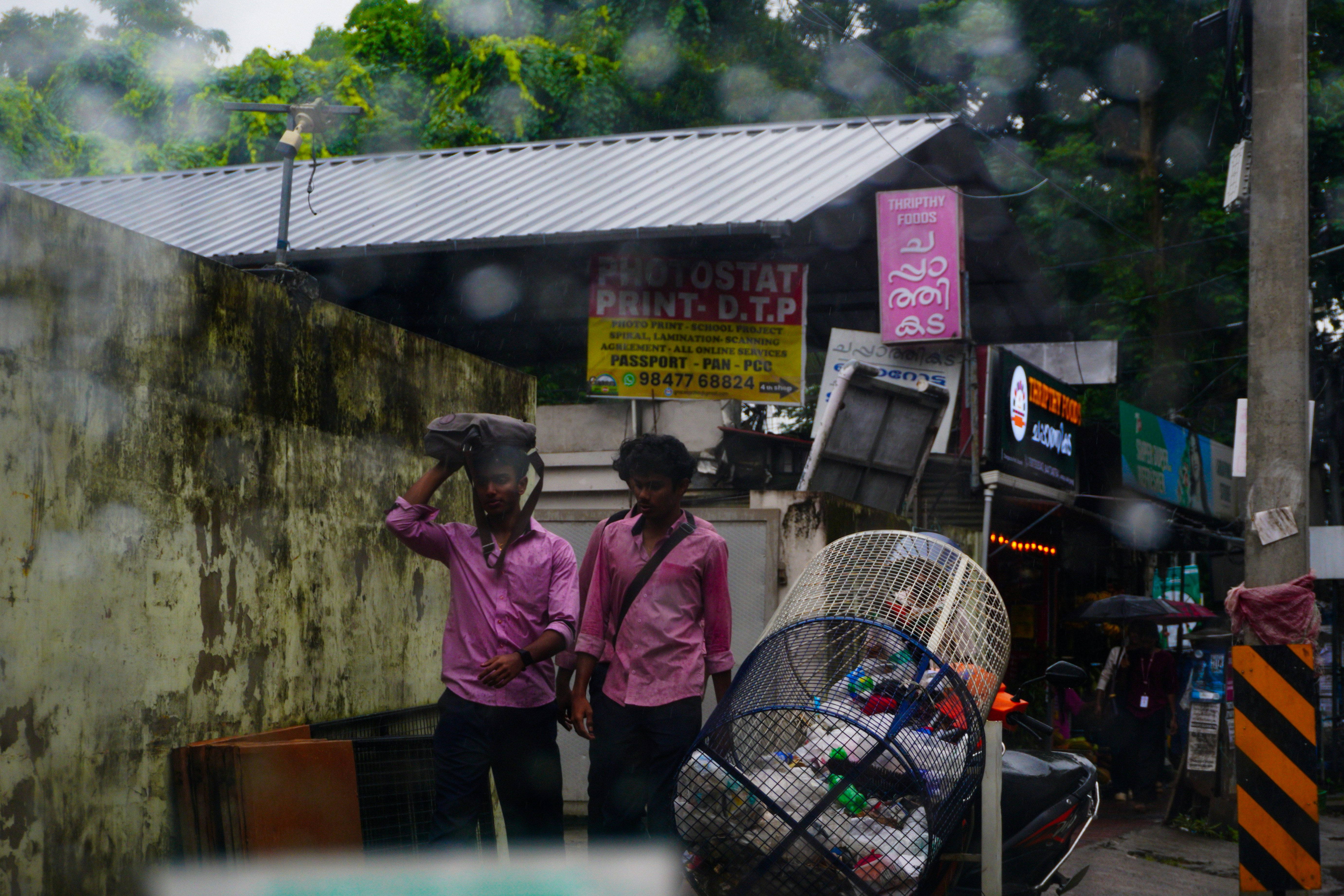 Pink-shirted wanderers under a market arc in a rain-washed lane