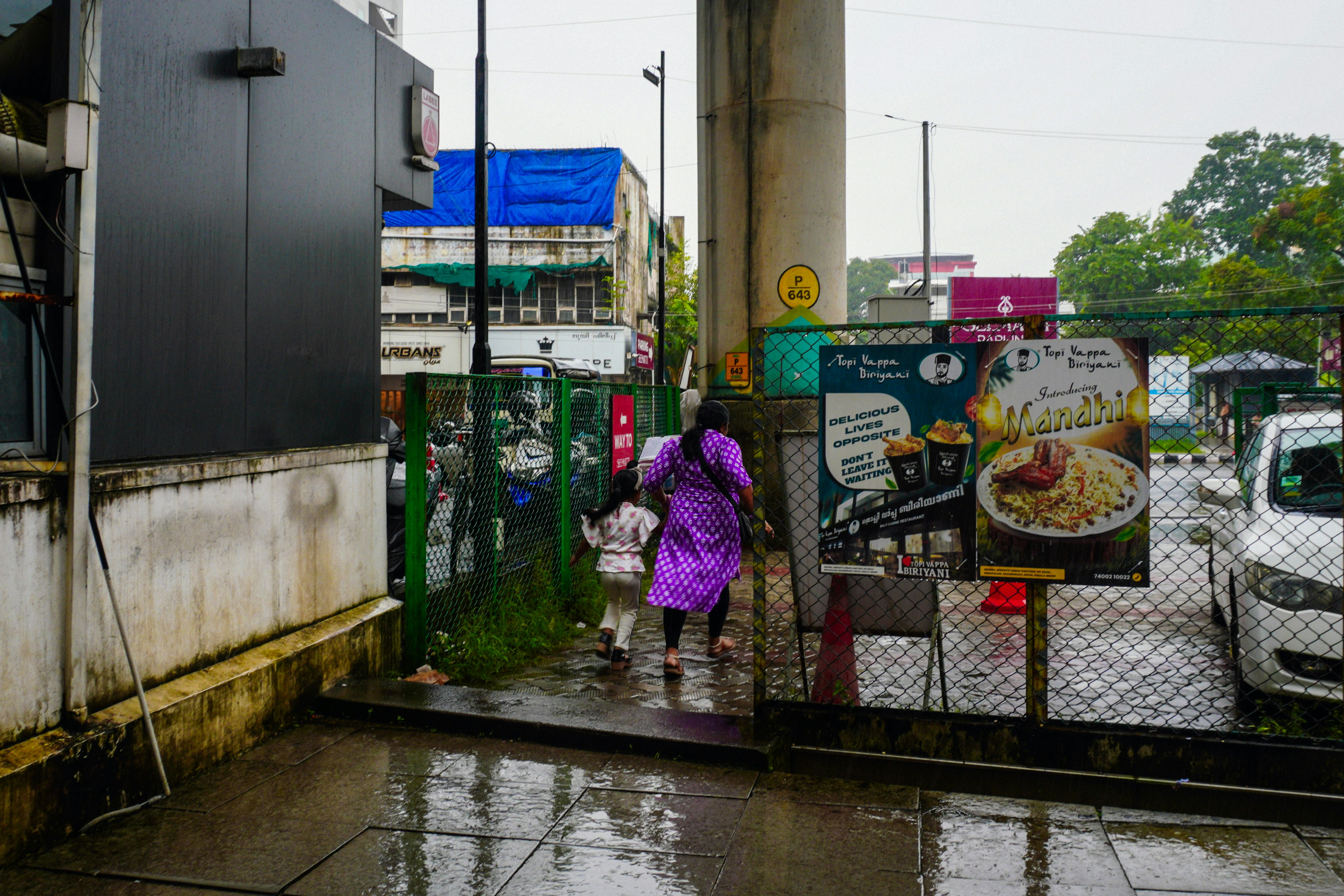 Rainy Street Crossing: Family in a Purple Coat by the Gate