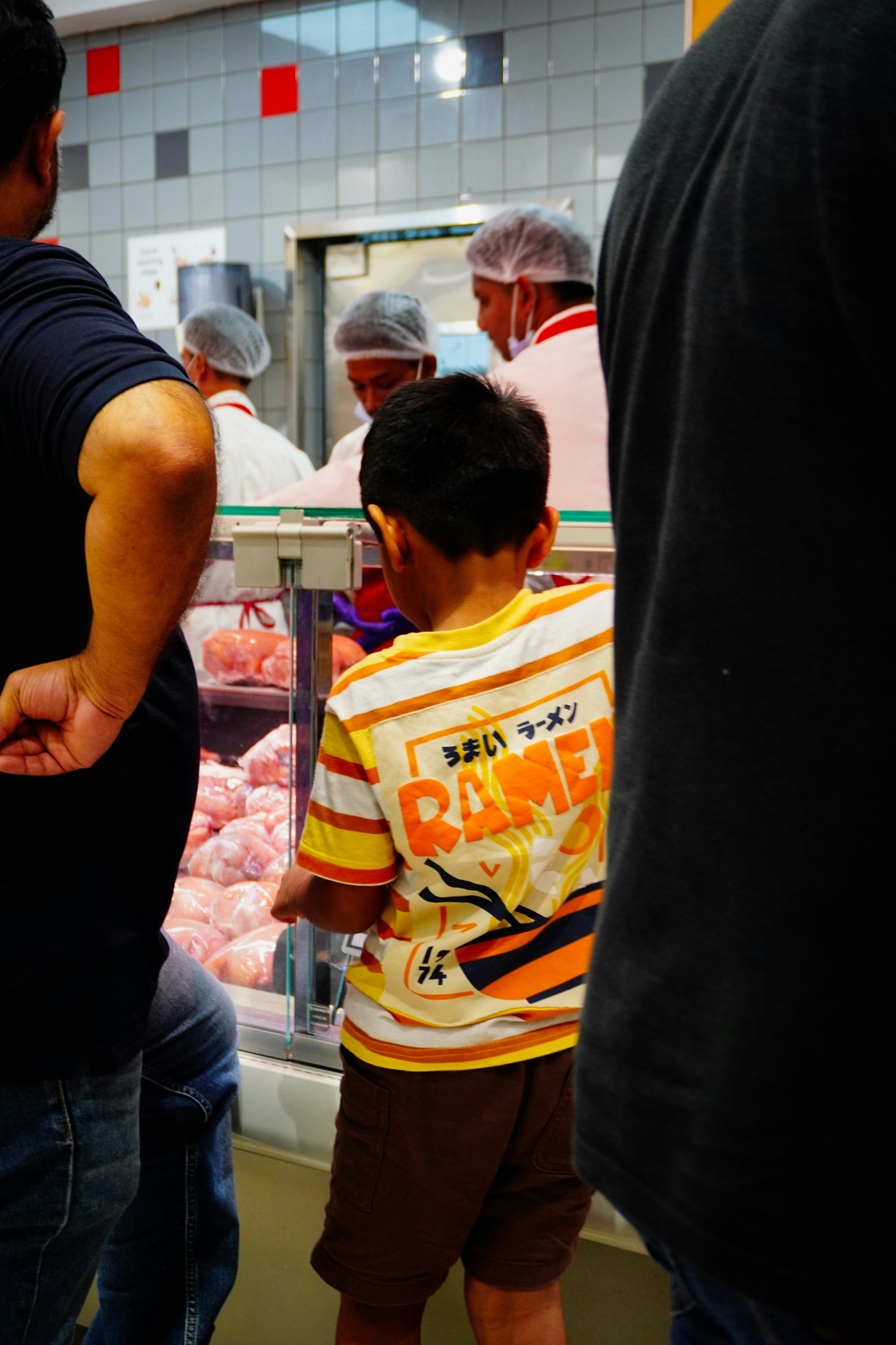 Cafe counter encounter: a boy in a striped shirt waiting at the meat display