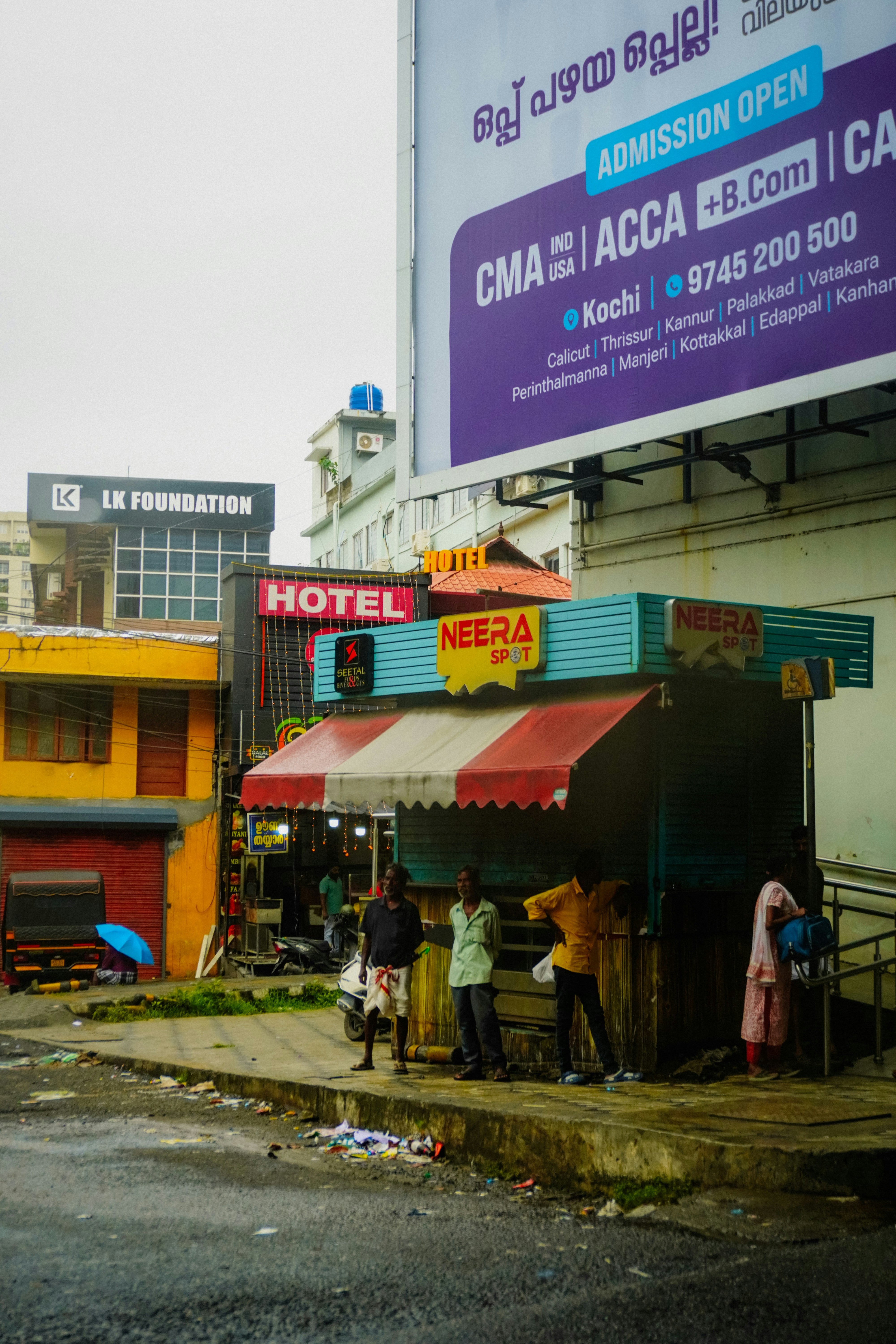 Neon Signage Overhang and Street Shopfronts in a Rainy Indian Alley