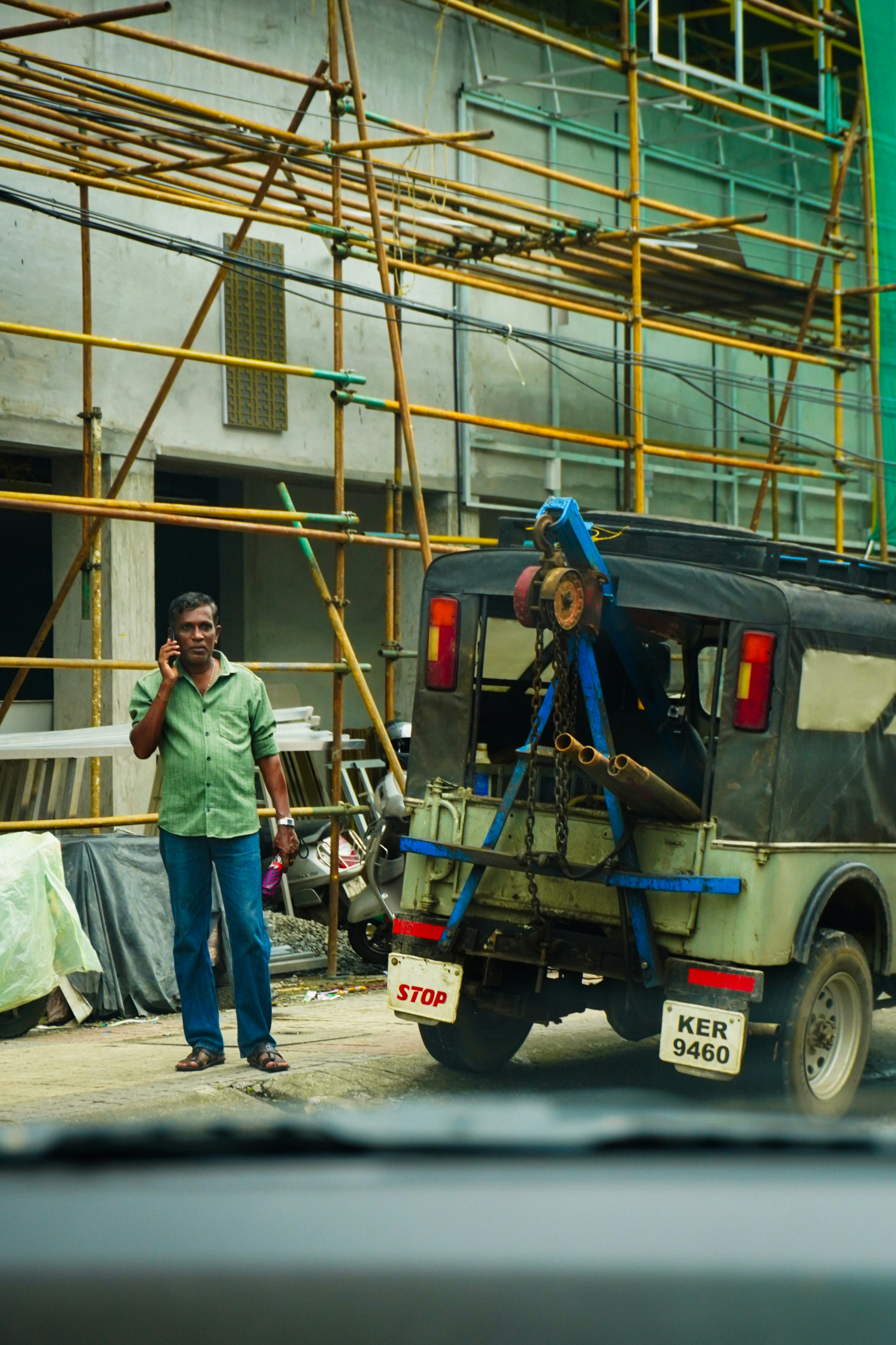 Worker on a construction site pauses to take a call beside a parked utility vehicle
