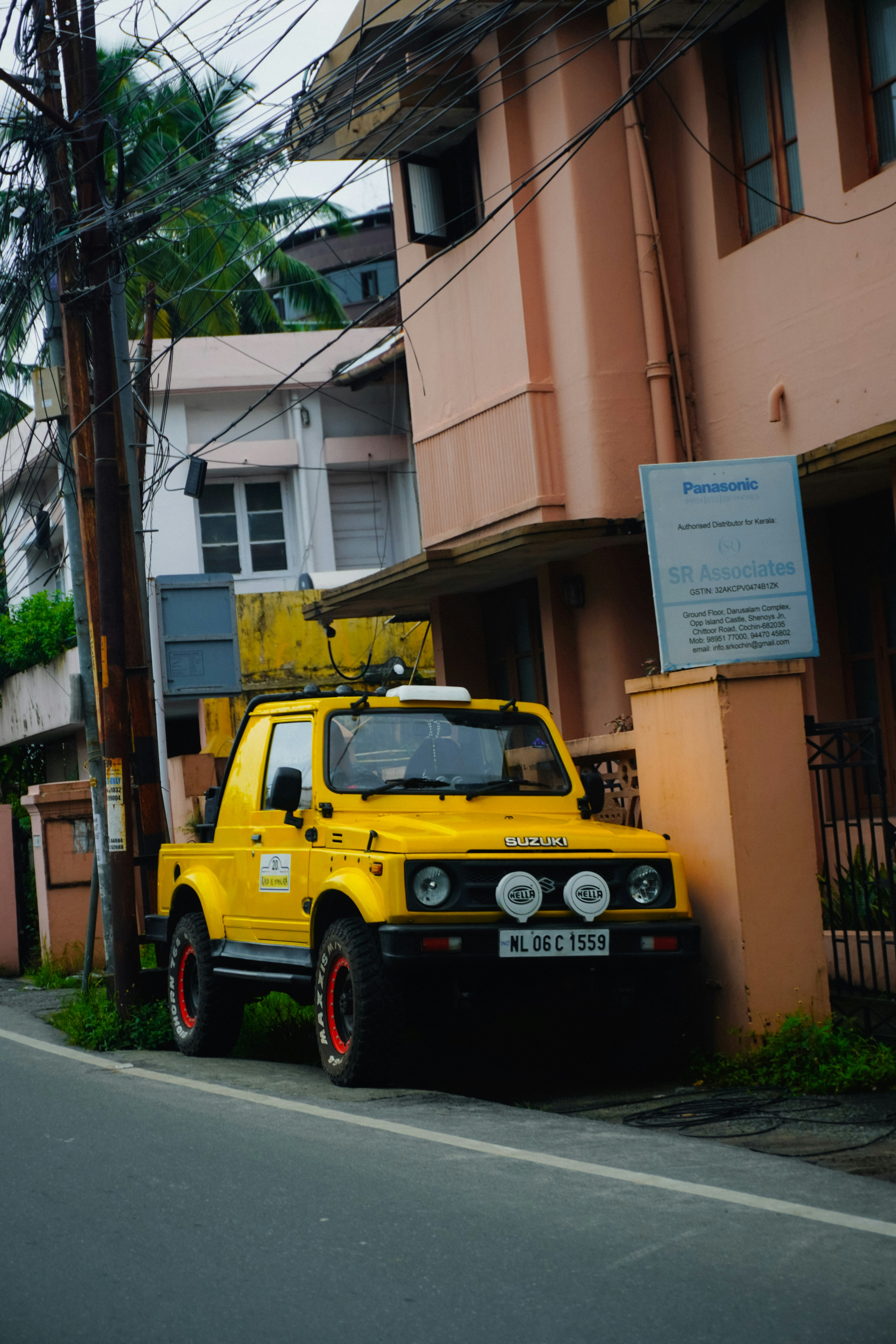 Yellow Utility: A Street-Front Suzuki Parked Beneath Wiring and Windows