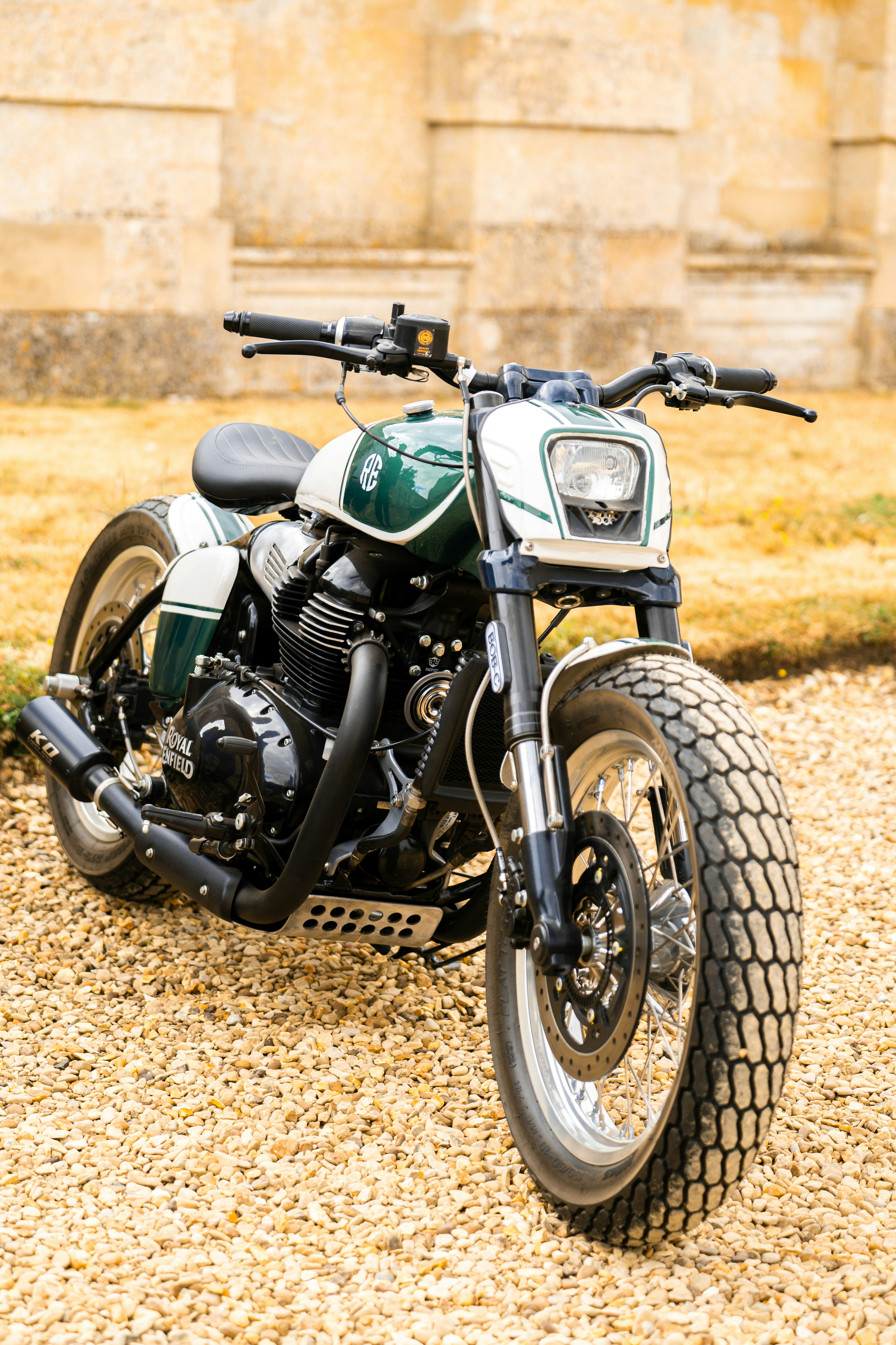 Green Flame: A Retro Royal Enfield Stands Quietly Amid Rustic Gravel