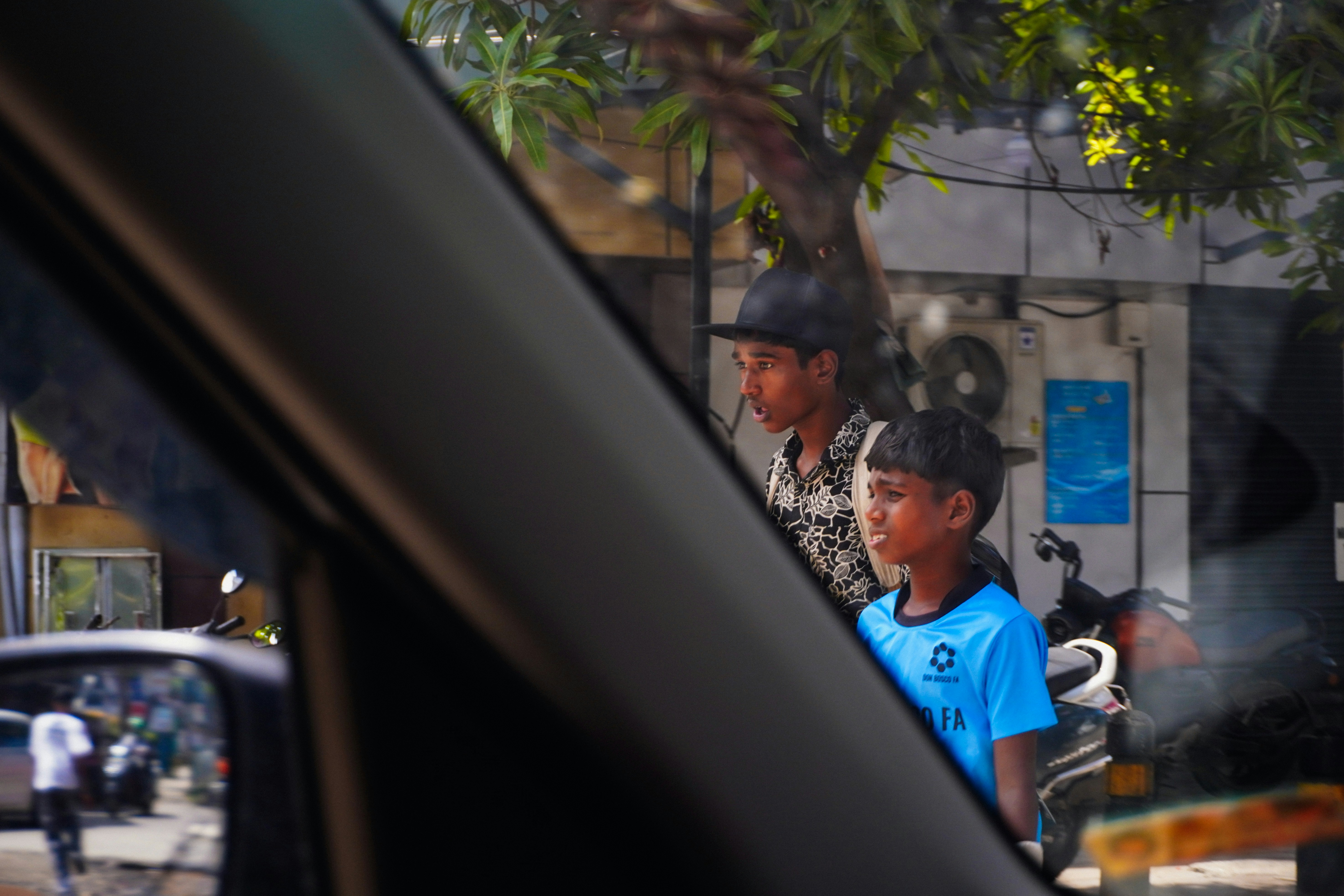 Masked moments: two pedestrians framed beside a car window