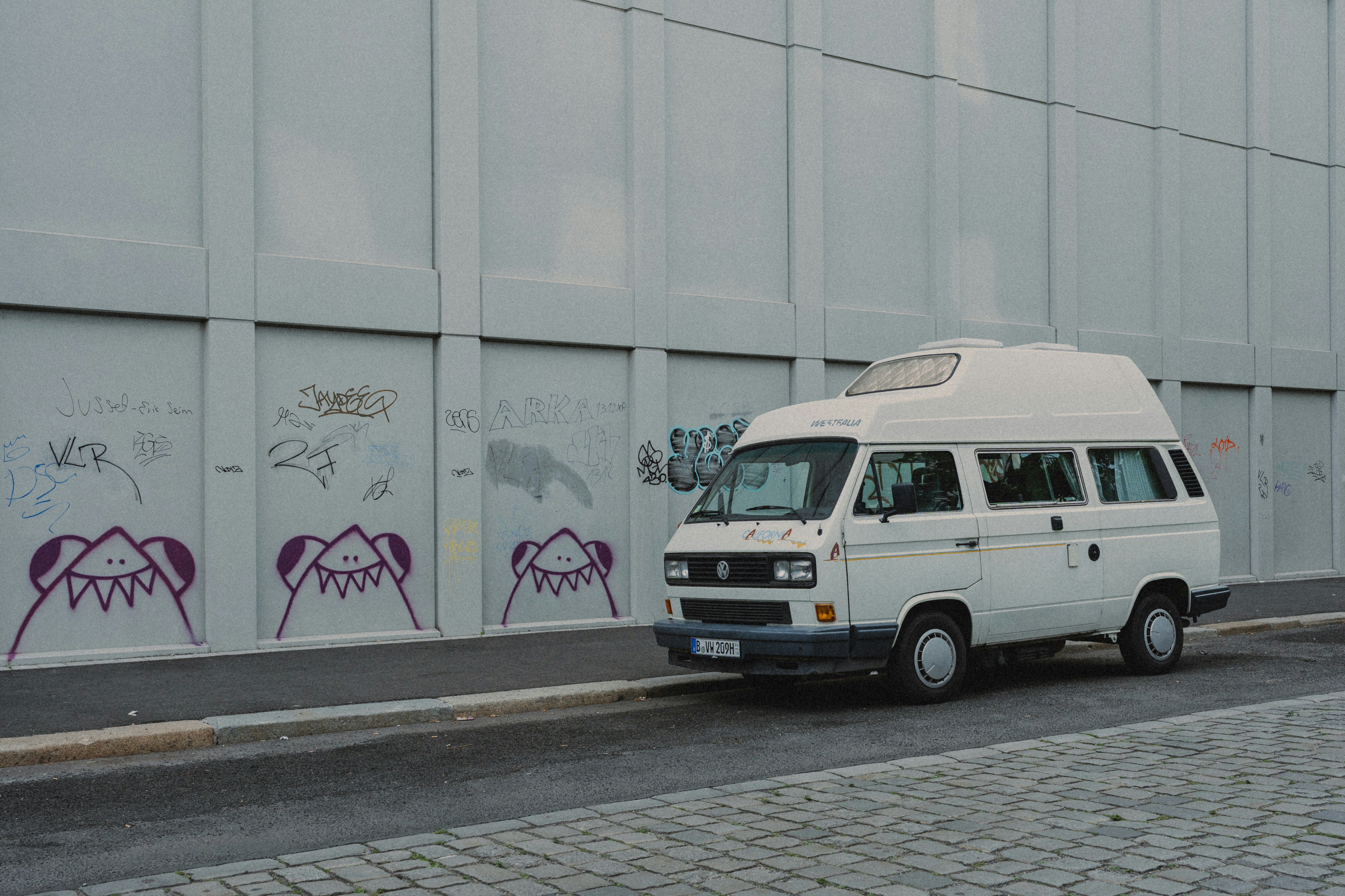 White Volkswagen Van Resting by a Graffiti Wall