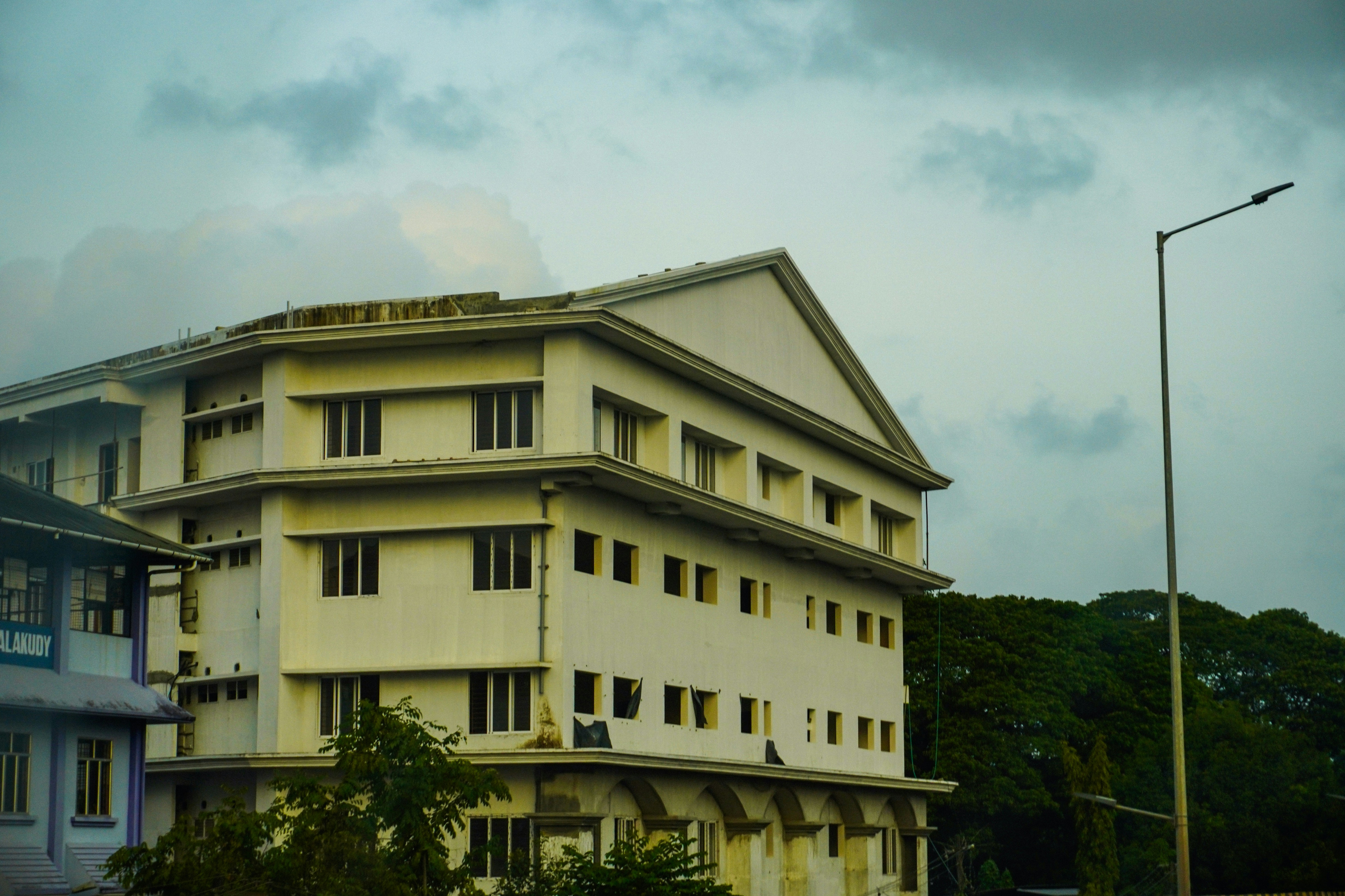 Sunlit colonial building amid a growing suburb under a pale sky