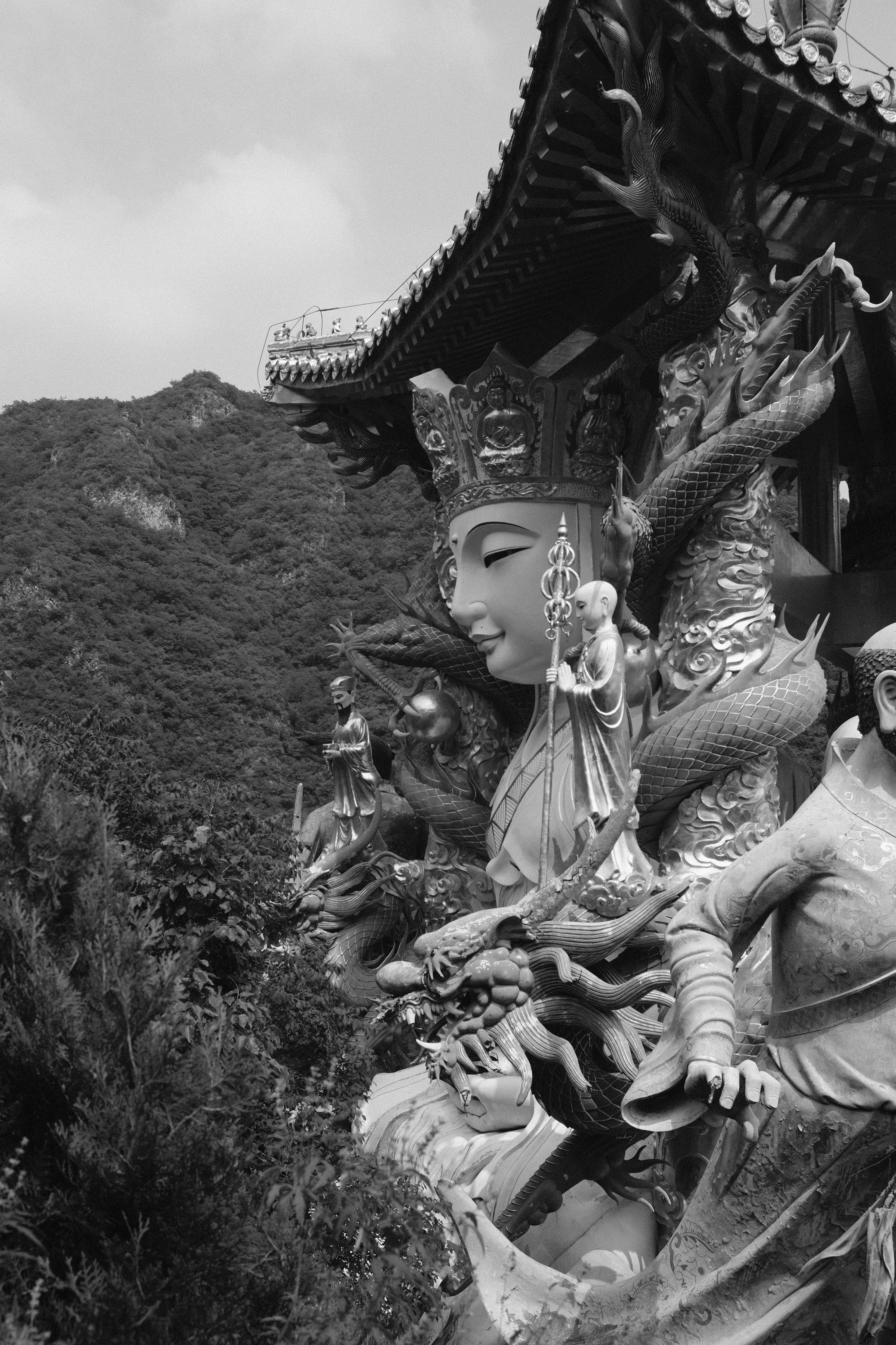 Dragon-guardian statue on a temple, perched above misty cliffs