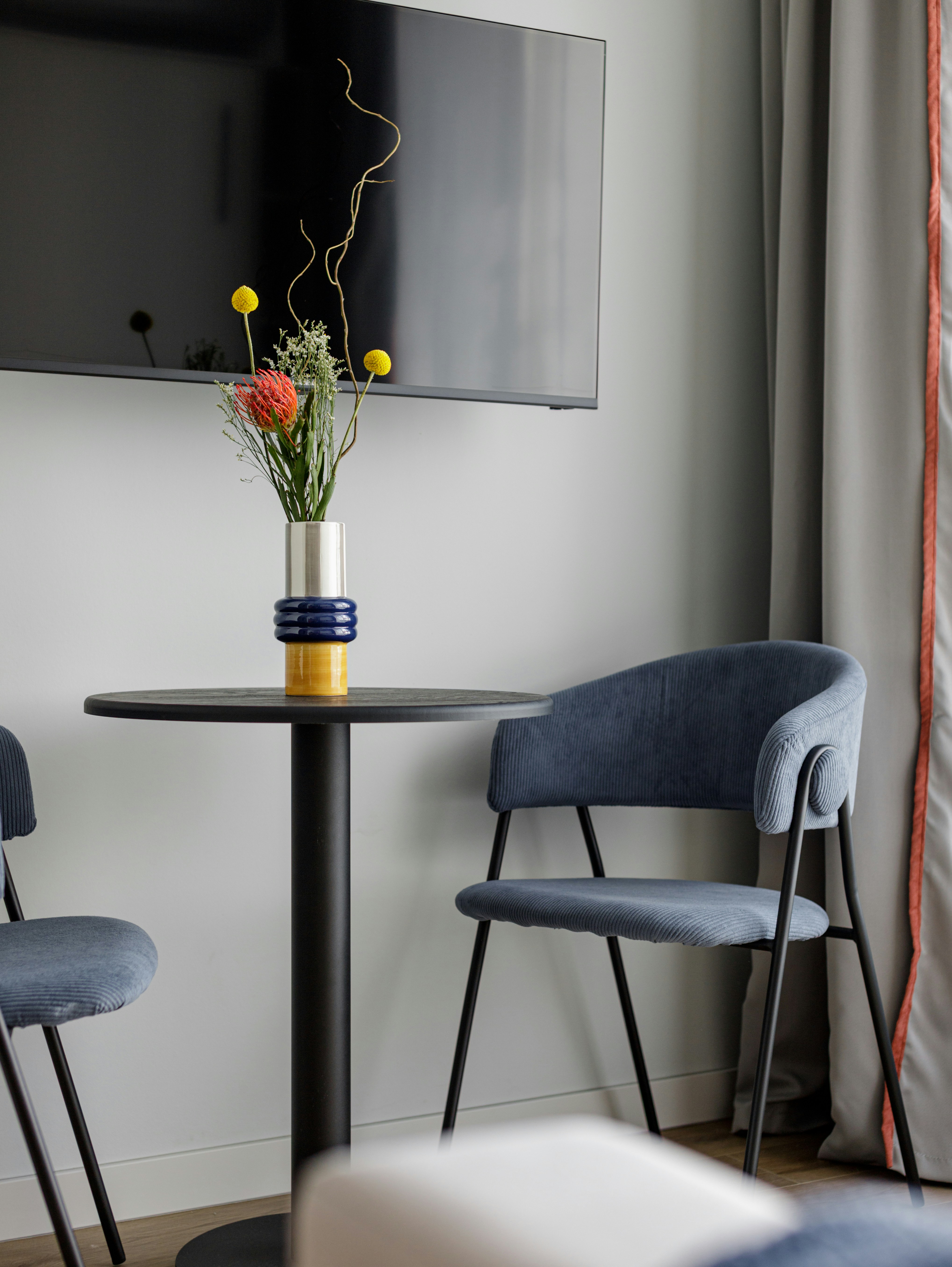 Minimalist Lounge: A Tall Vase on a Round Table Between Velvet Chairs