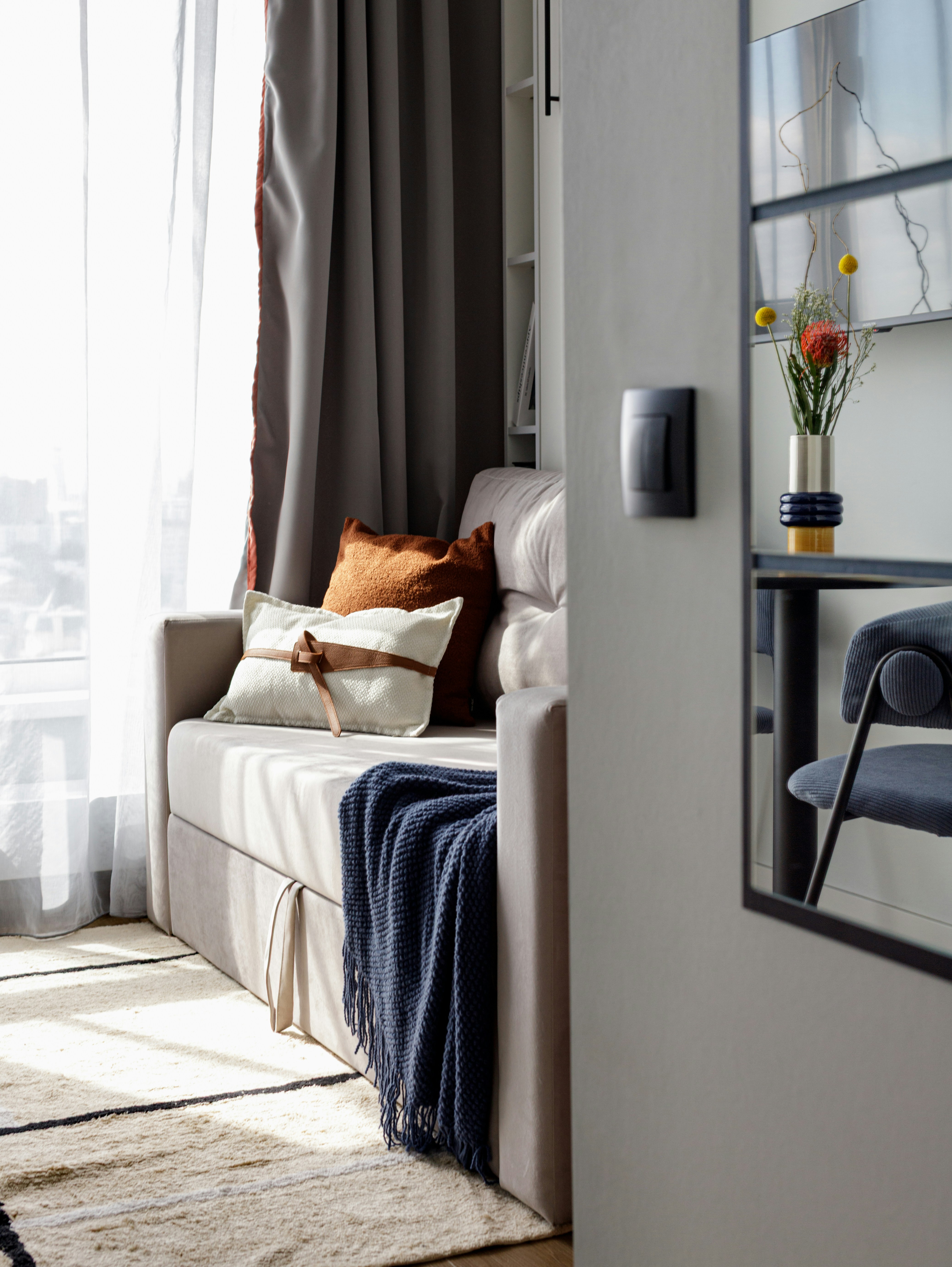 Sunlit Nook: Cozy Living Corner with Textured Throws and Fresh Vase