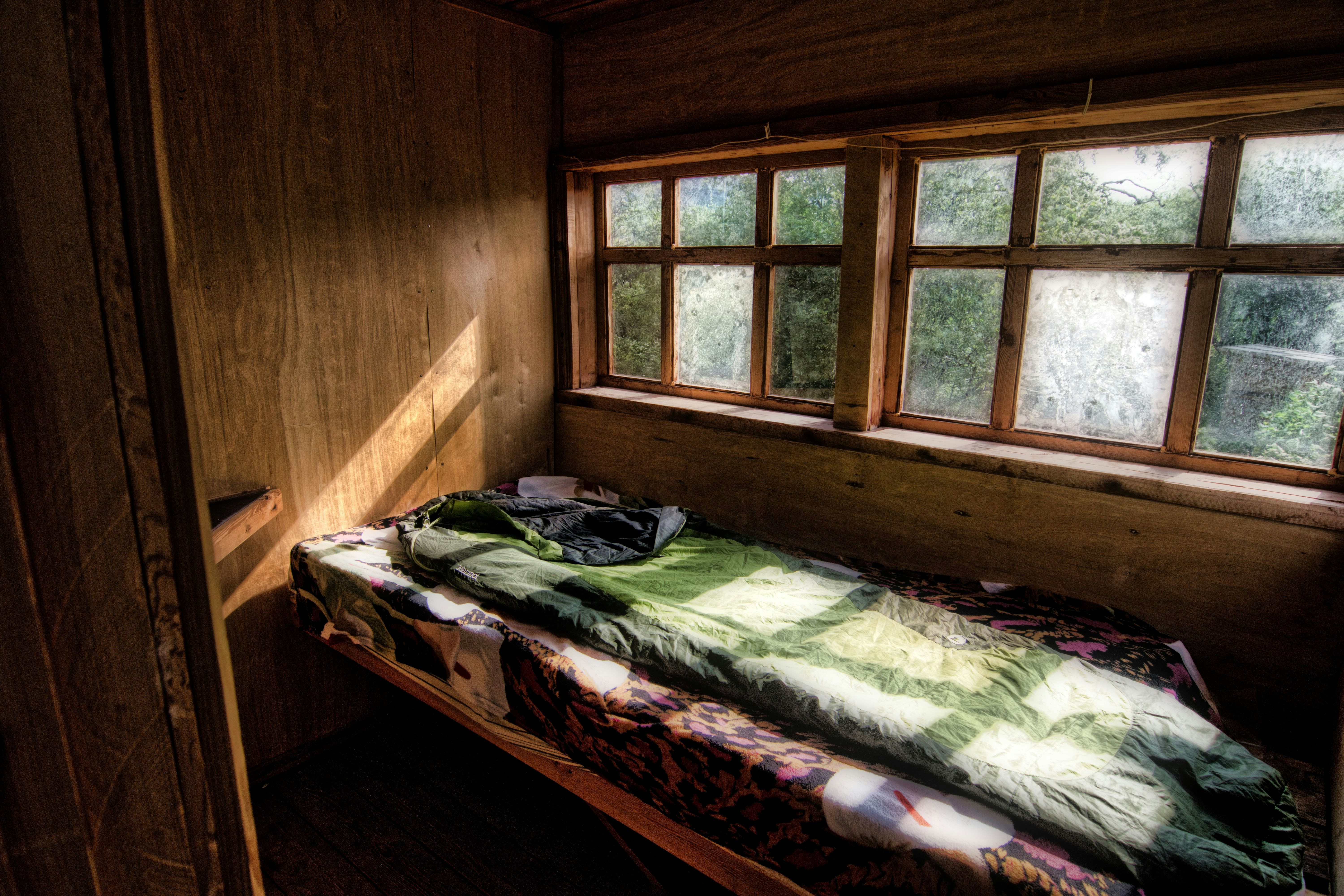Sunlit Tranquility: A Weathered Bed in a Quiet Woodshed