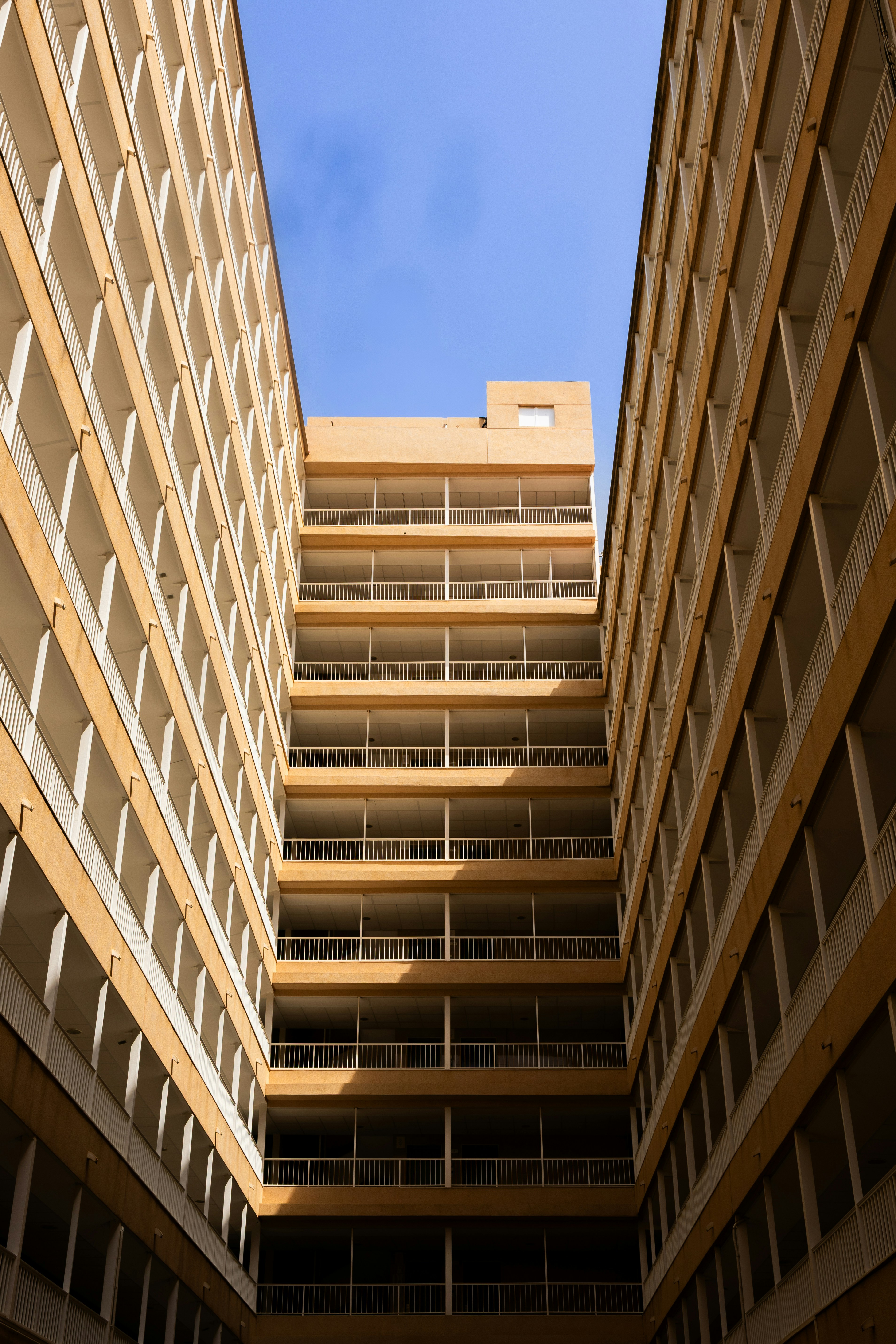 Symmetrical Atrium Ascent Between Sunlit Balconies