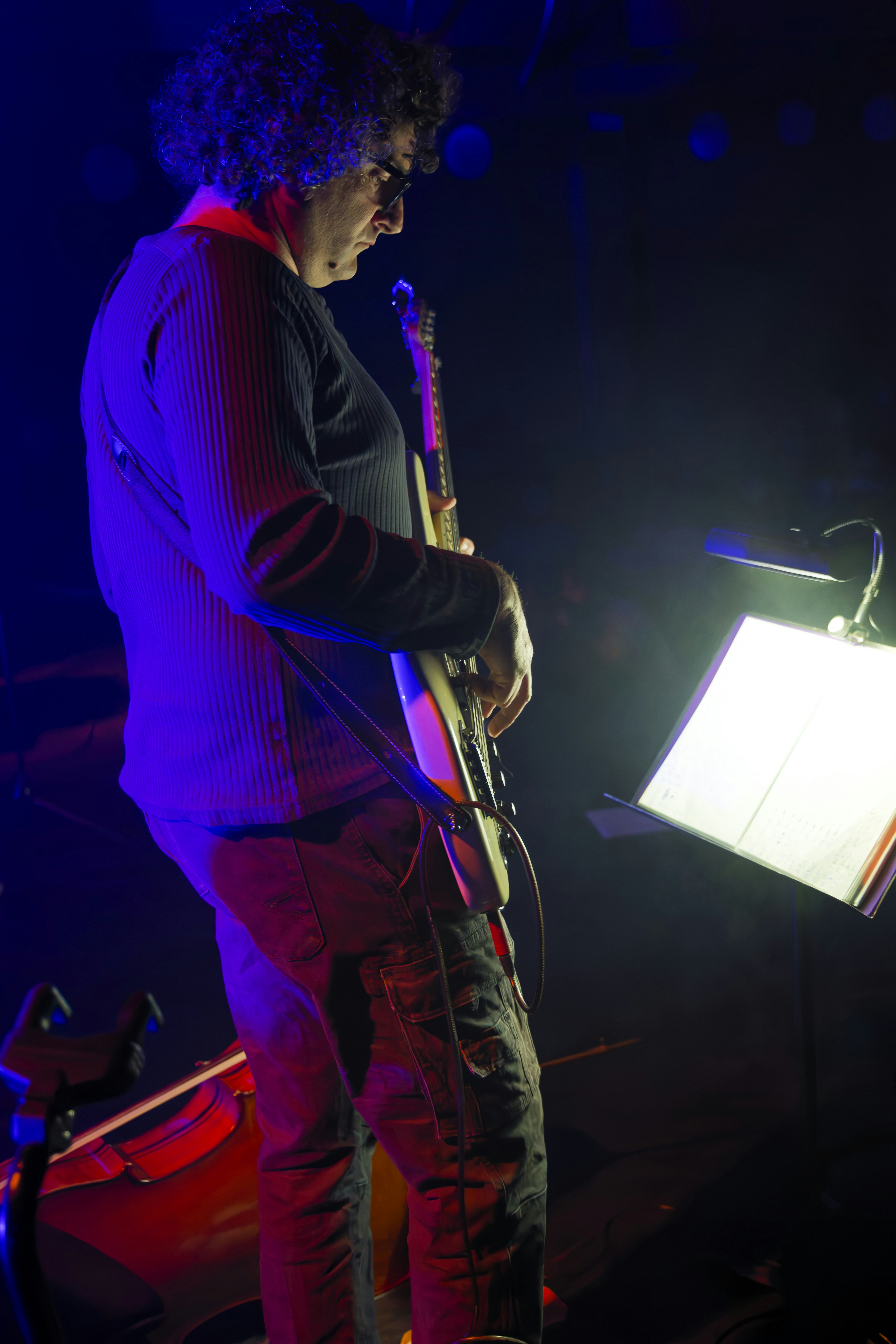 Guitarist in Neon Blue: Focused on Strings Under Stage Glow