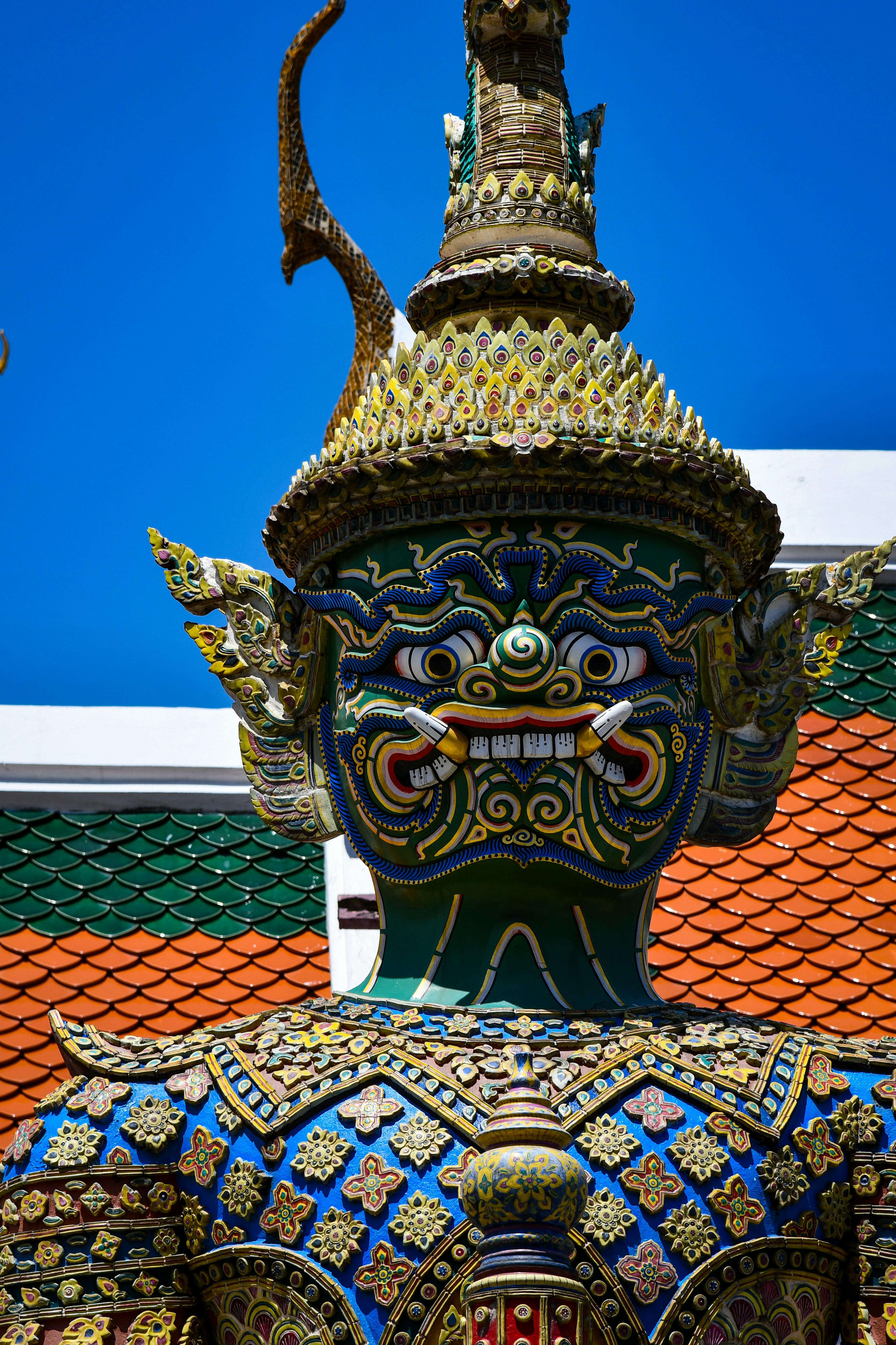 Emerald Guardian: The Multicolored Demon's Mask Against a Cerulean Sky