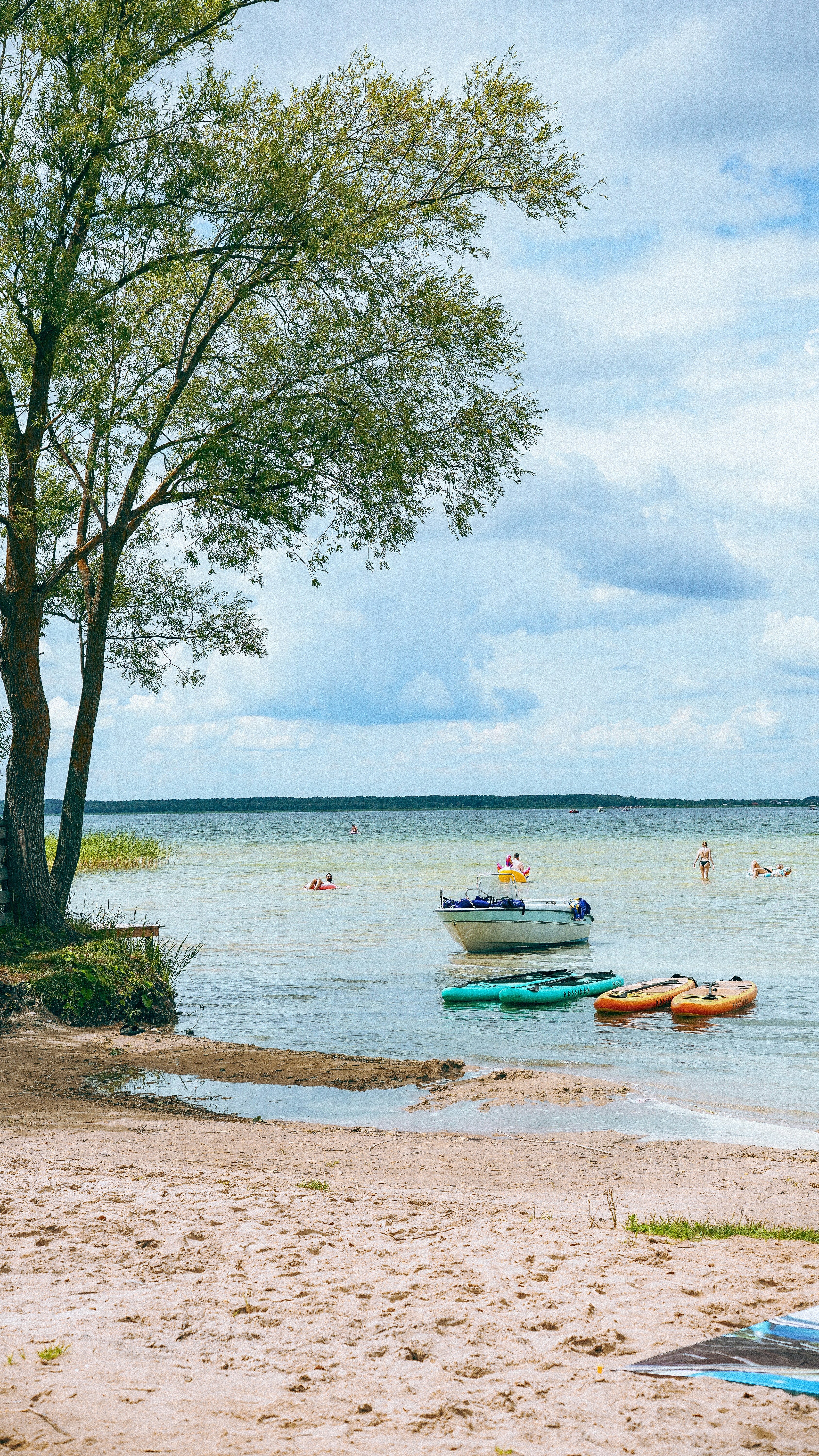 Lounging by the Lake: A Quiet Beach Scene with a Boat and Kayaks