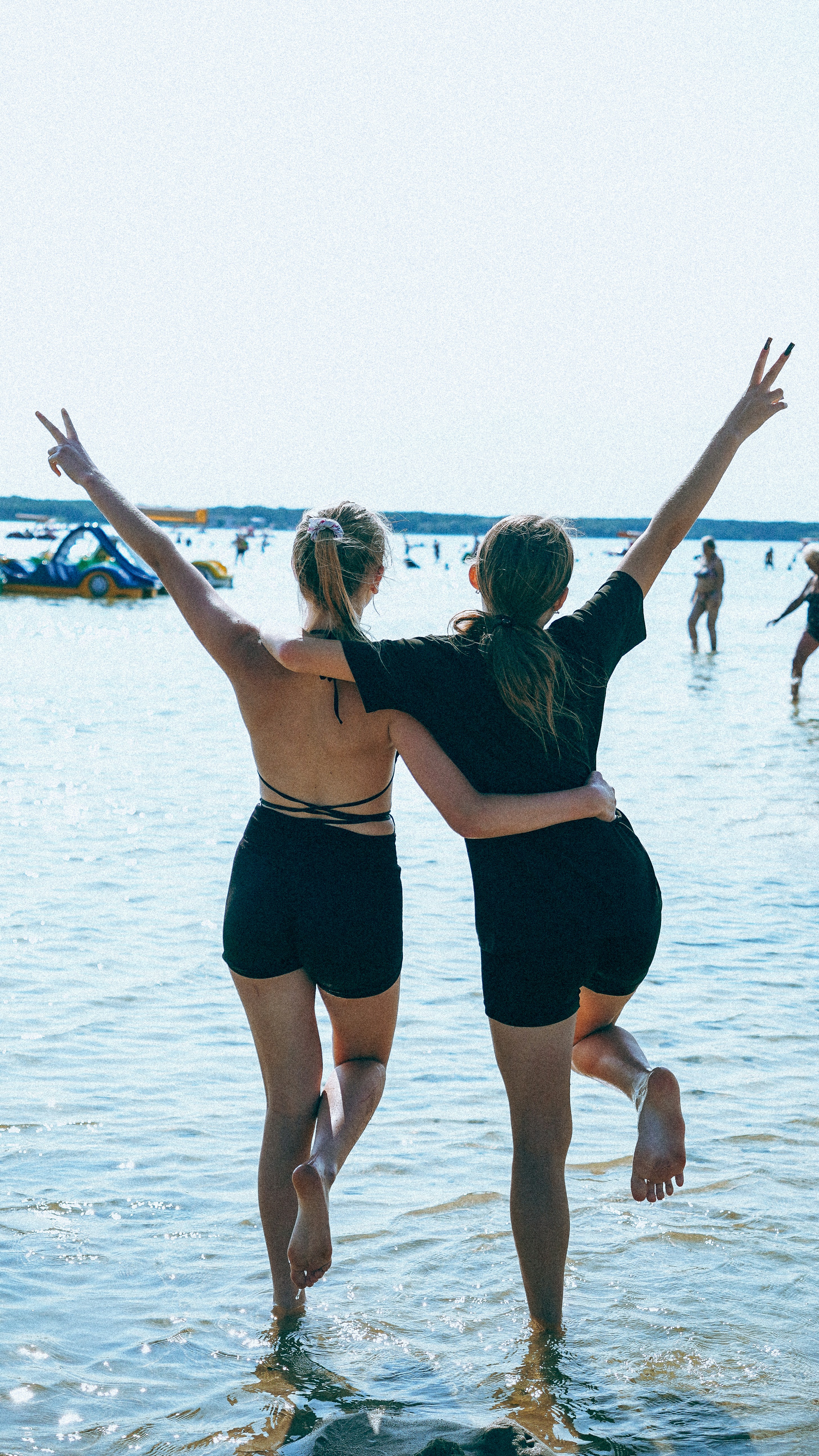 Two young women making peace signs in the water.