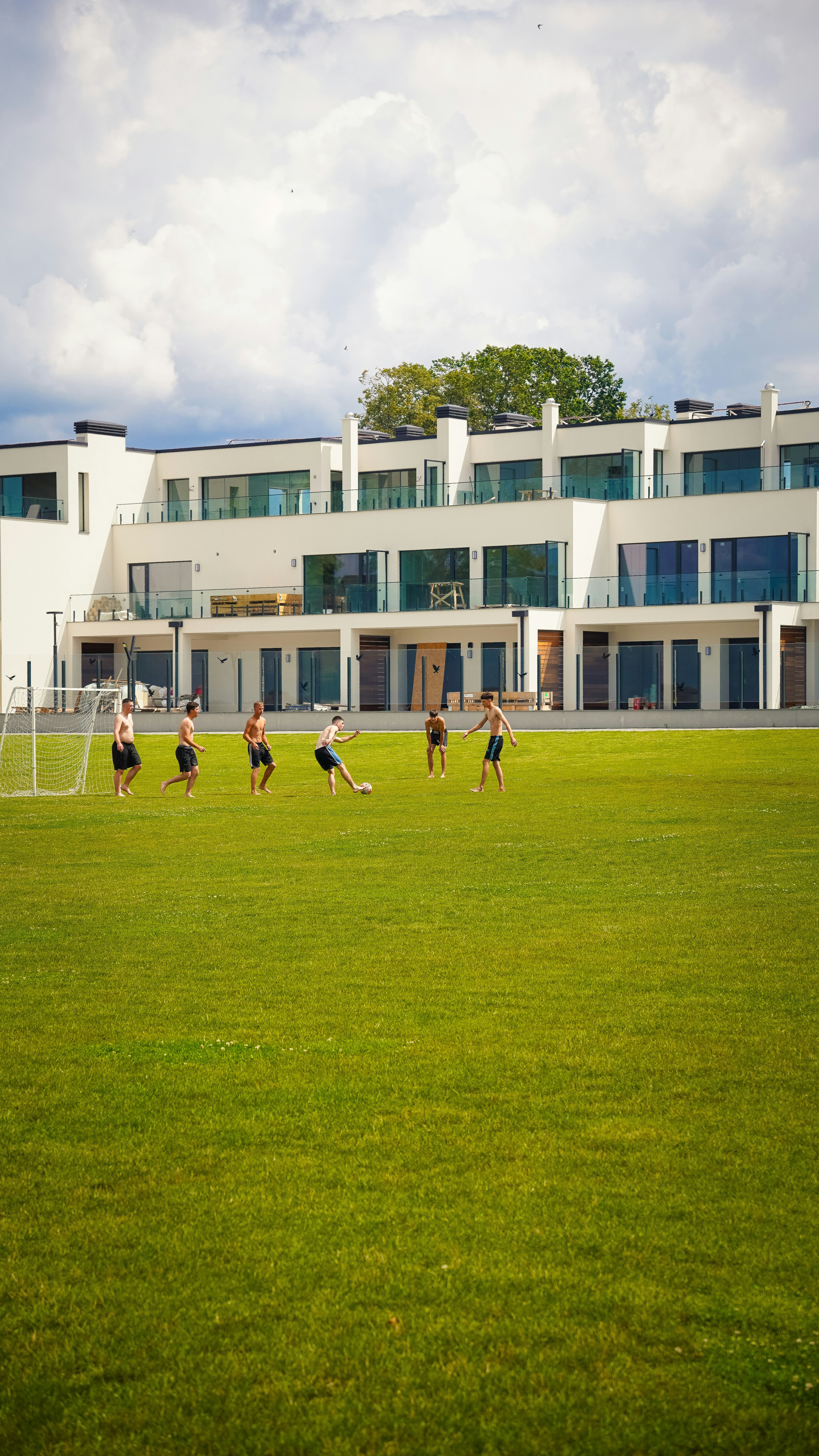 Courtyard Kickoff: Arow of players on a sunlit field in front of modern apartments