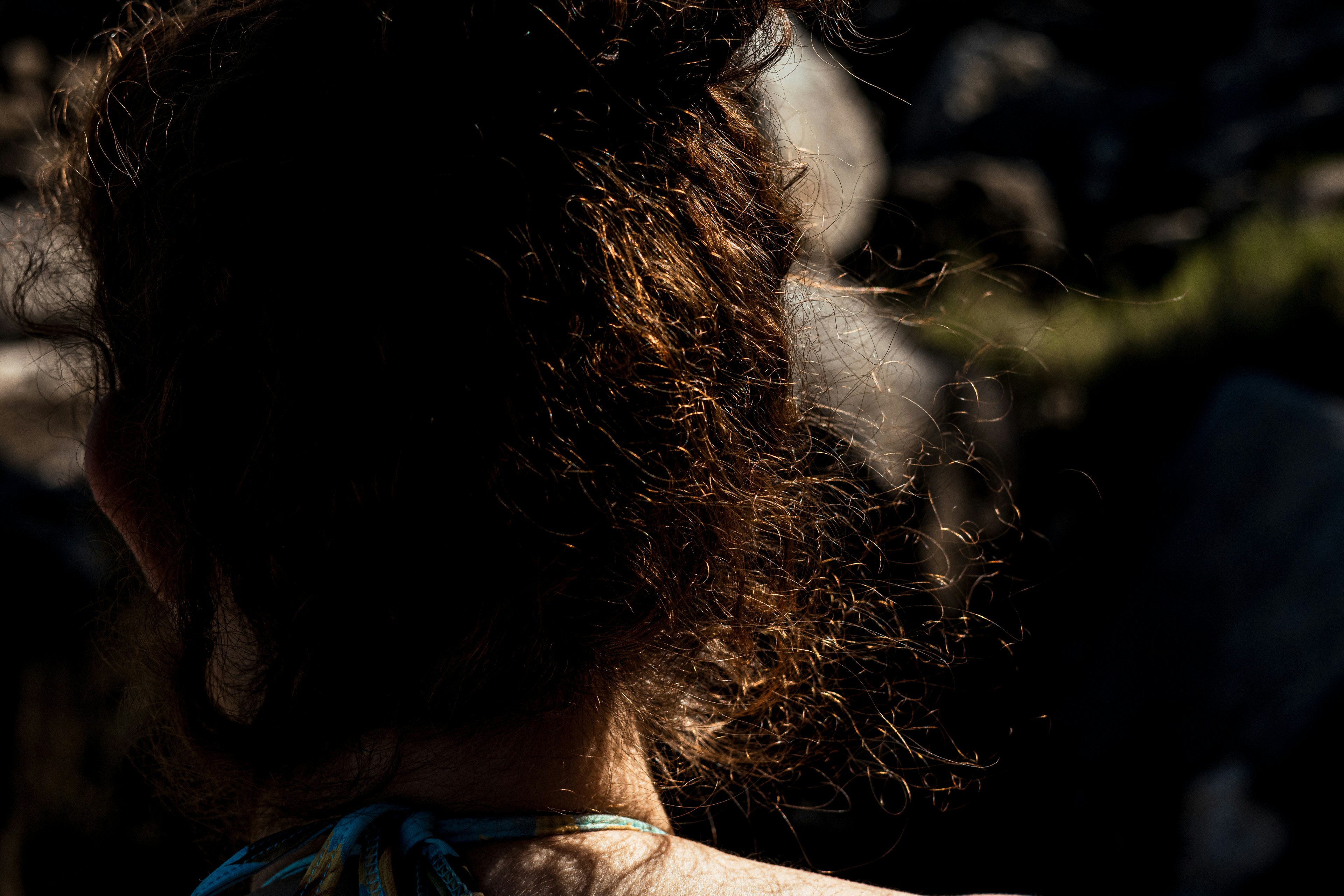 Backlit Evening Portrait: Curly Hair Silhouette Against Dark Fabric