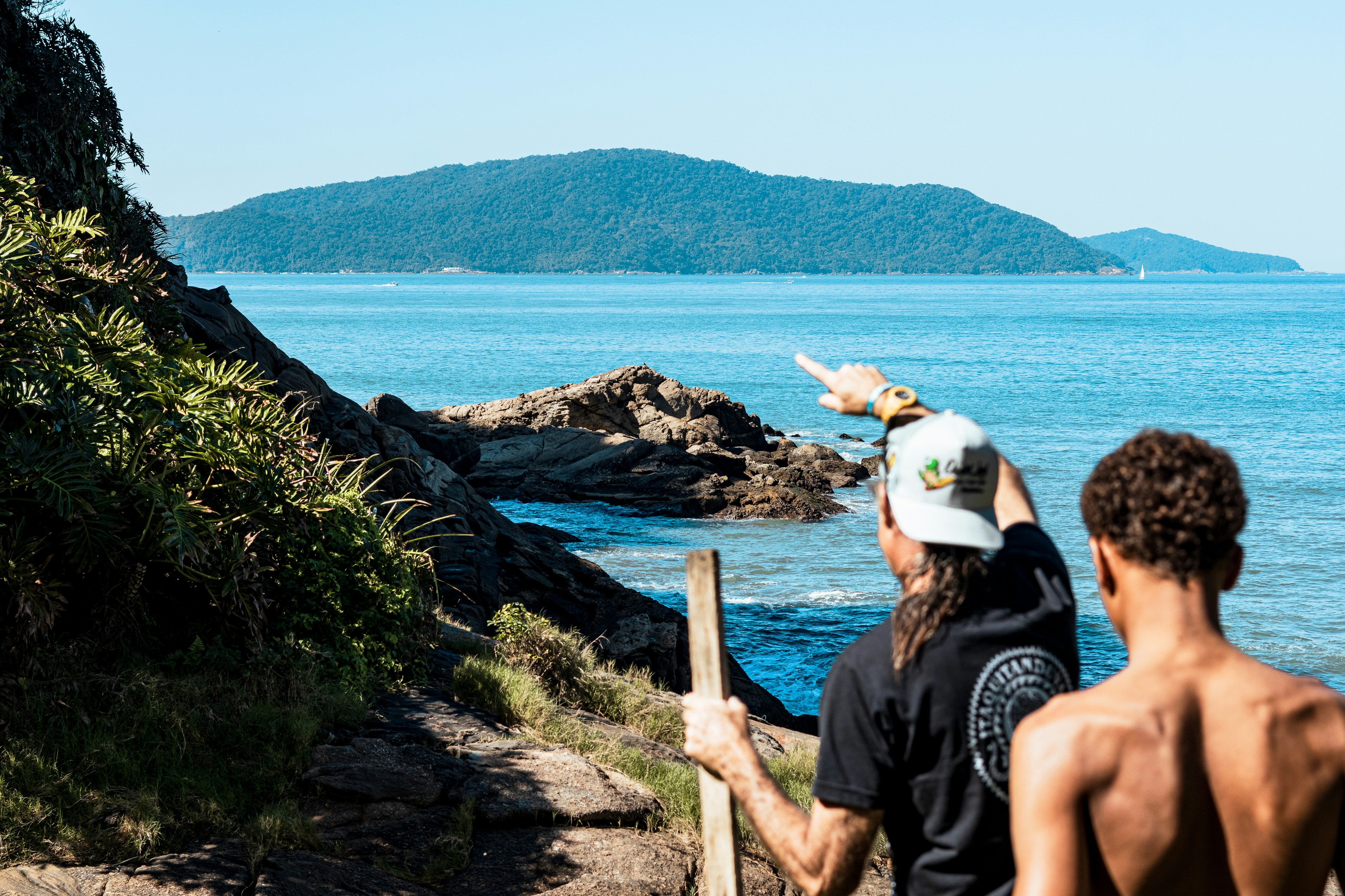 Coastal overlook: two surfers scouting the horizon from rugged shoreline