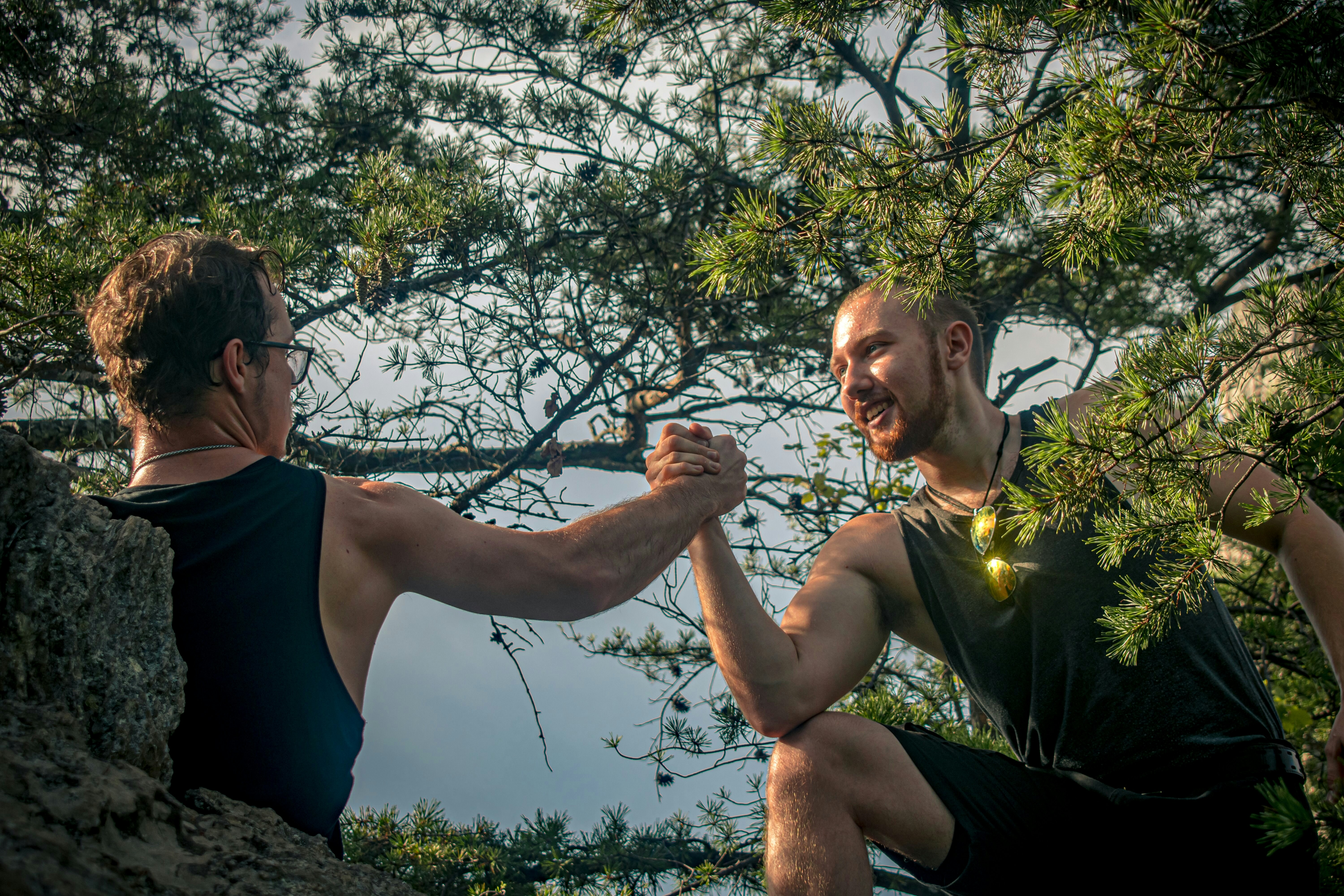 High-Five on the Clifftop: Two Friends Fill the Frame with Victory Sky