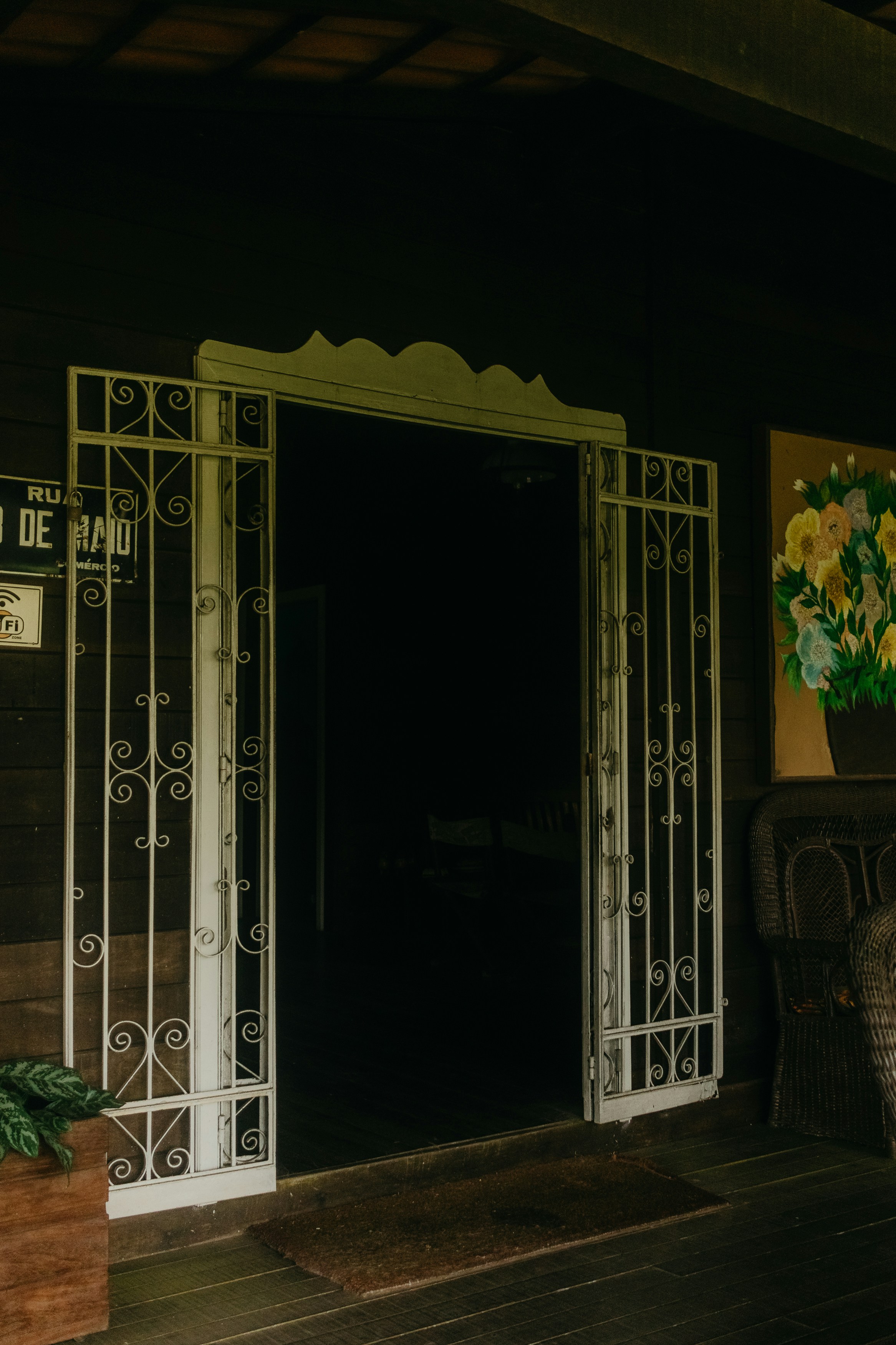 Open doorway into a quiet veranda with ornate ironwork