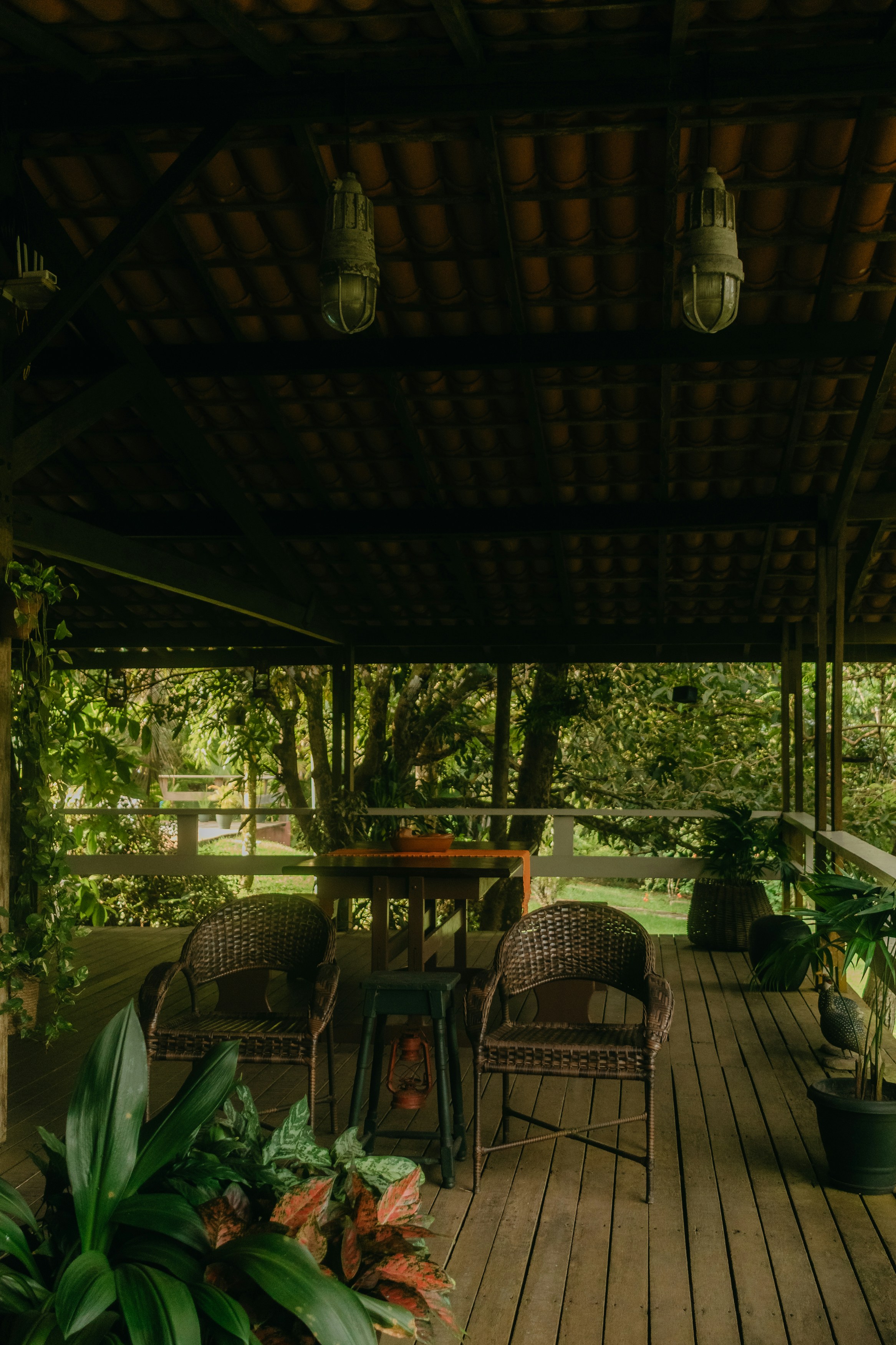Shaded teak veranda with woven chairs and lush greens