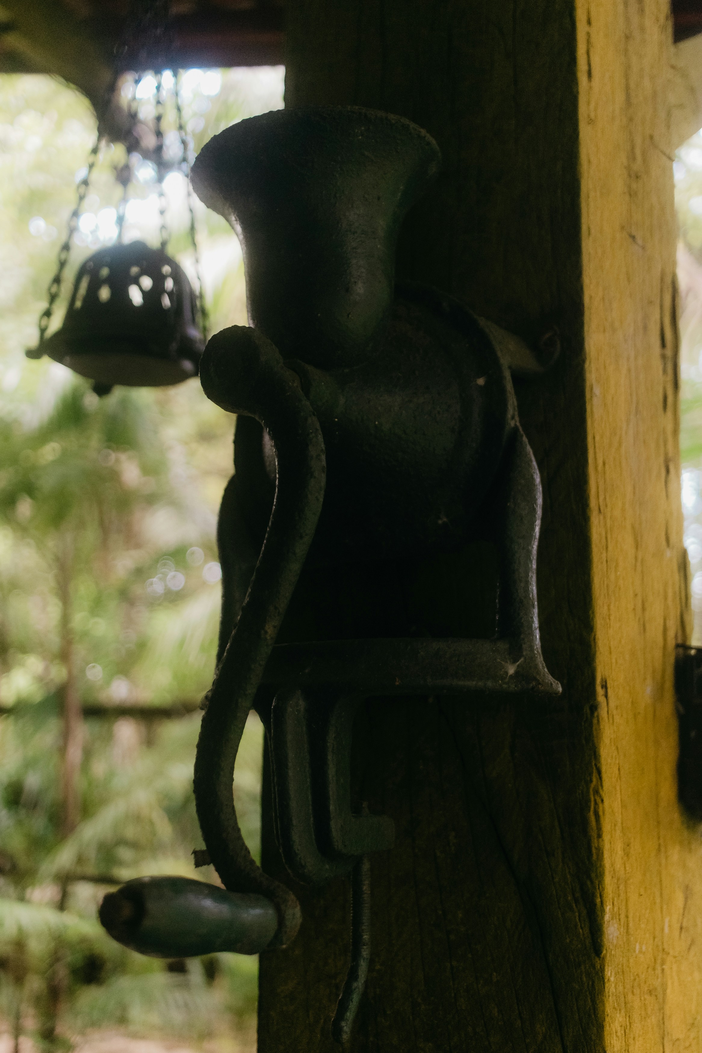 Rusty mill handle against a wooden post in dappled light