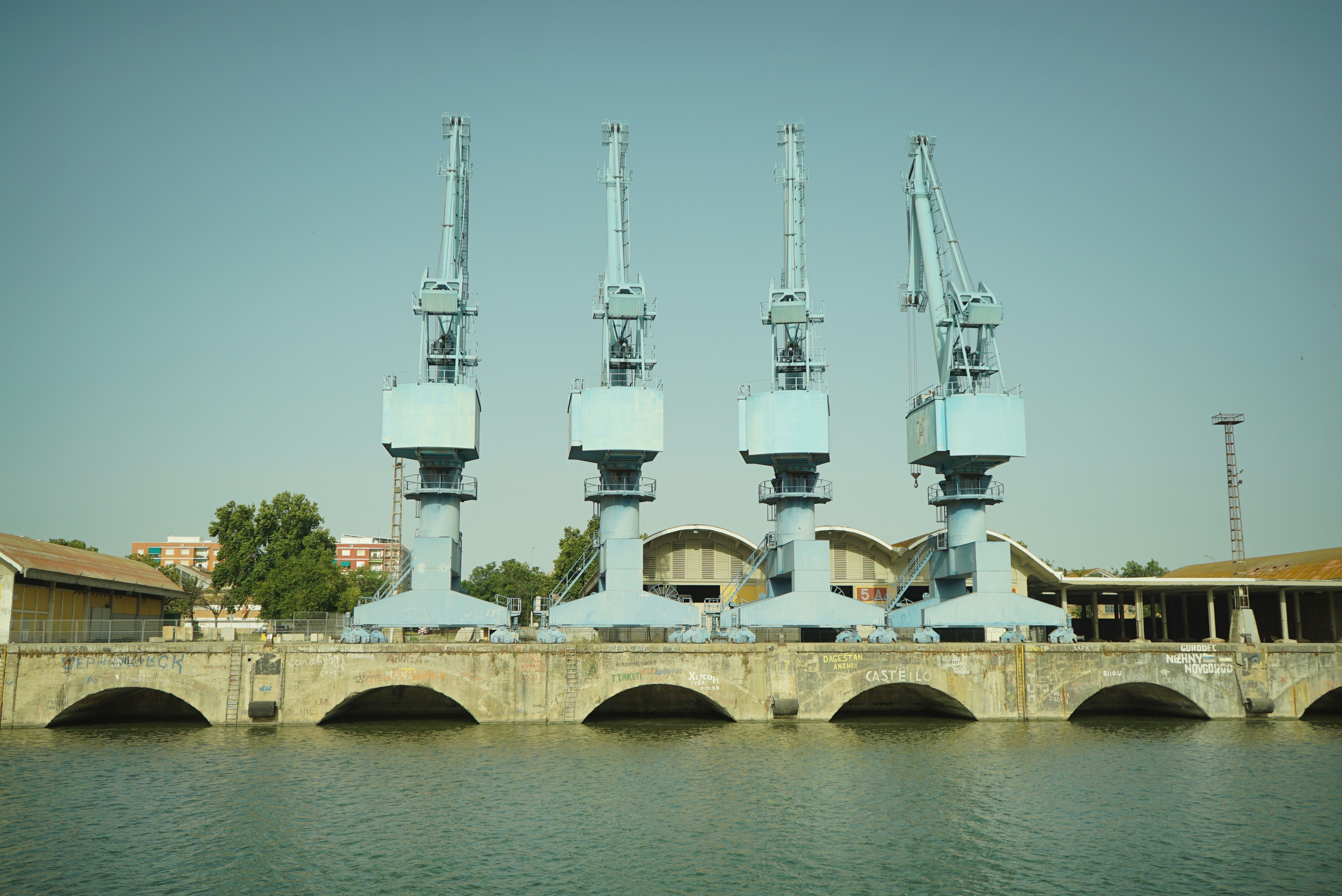 Industrial Giants Over the River: cranes lining a calm waterfront