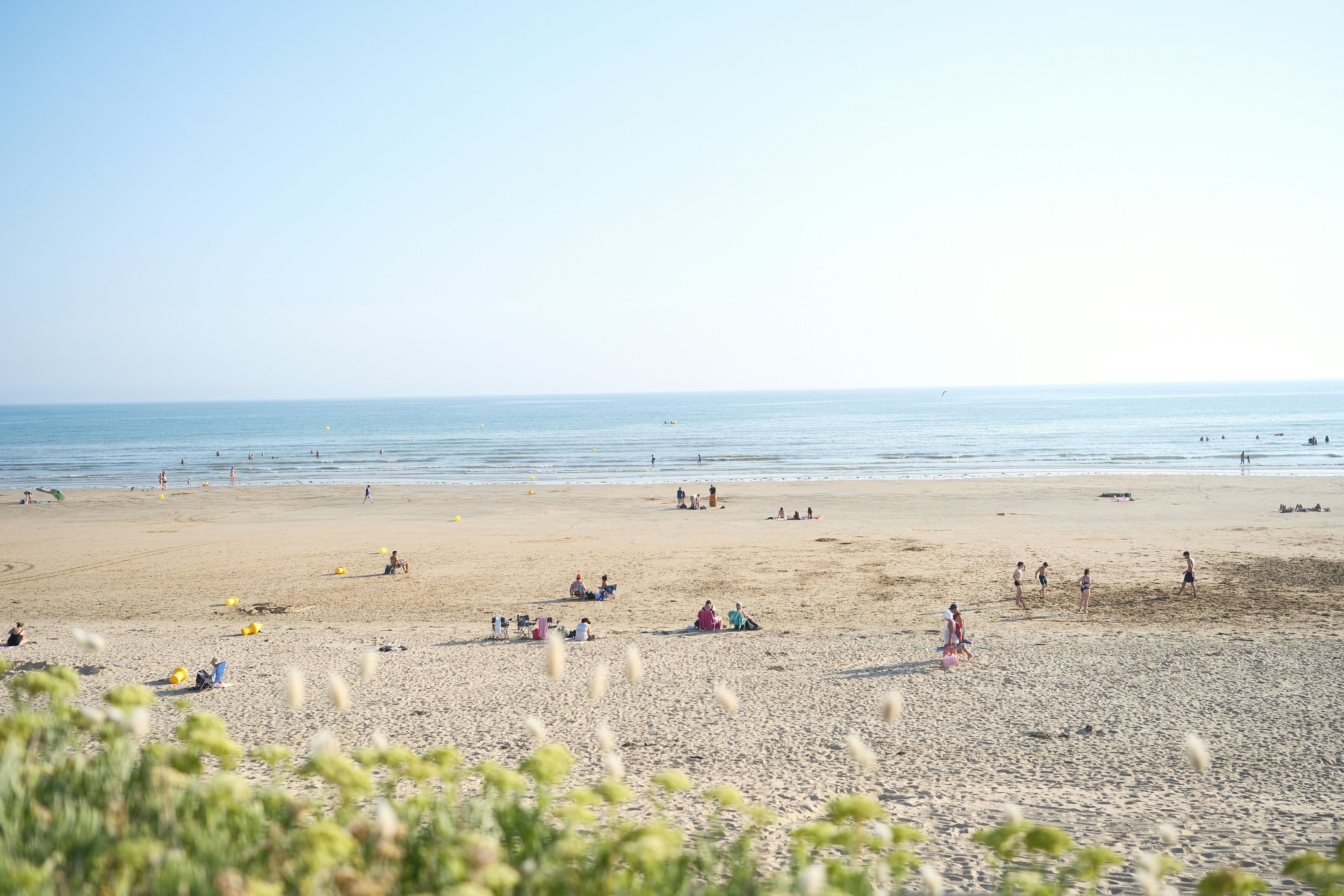 Sunlit Shoreline: Quiet Beachgoers Scatter Light Across a Distant Sea