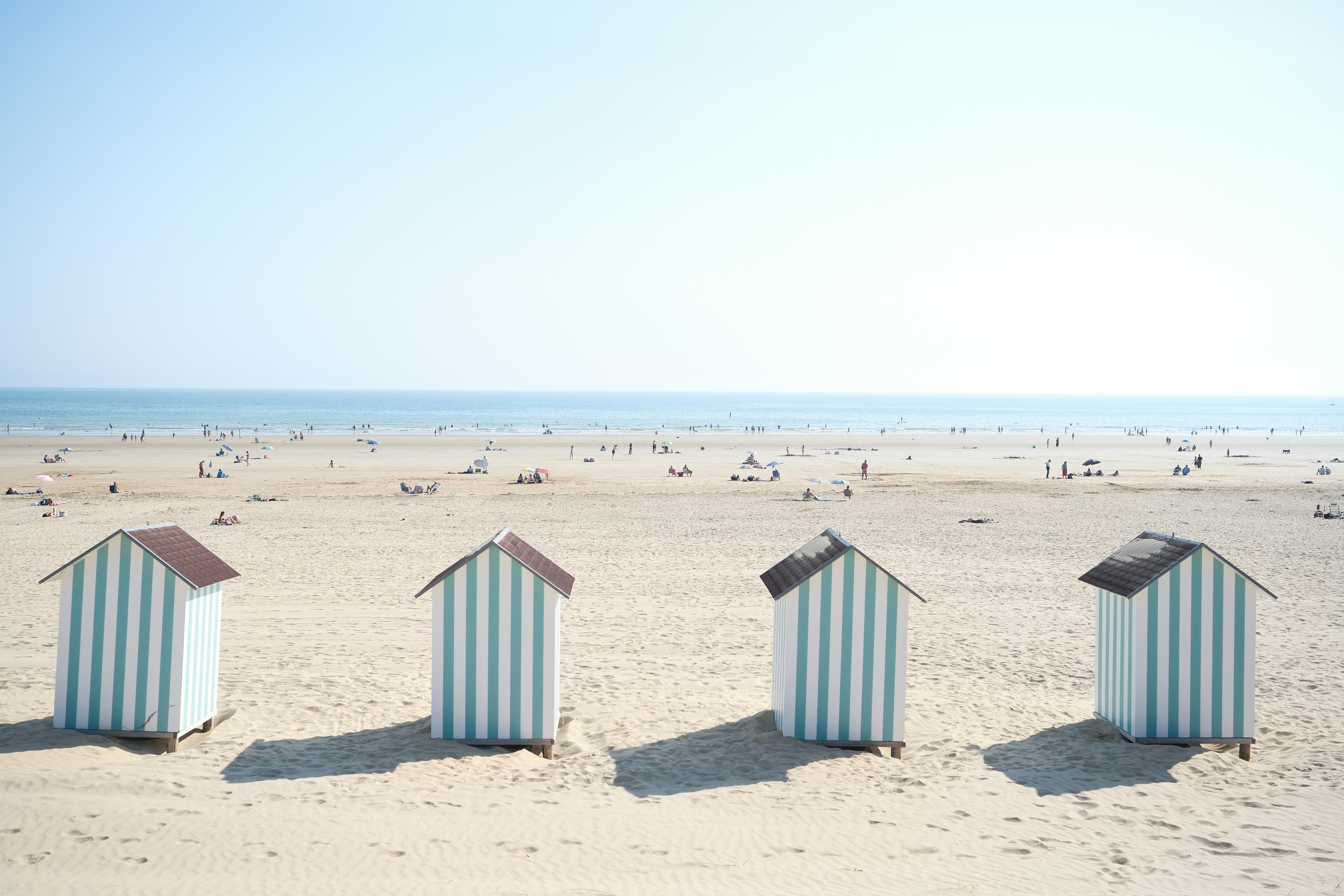 Stride of Stripes: Four Beach Cabins Line a Sunlit Shore
