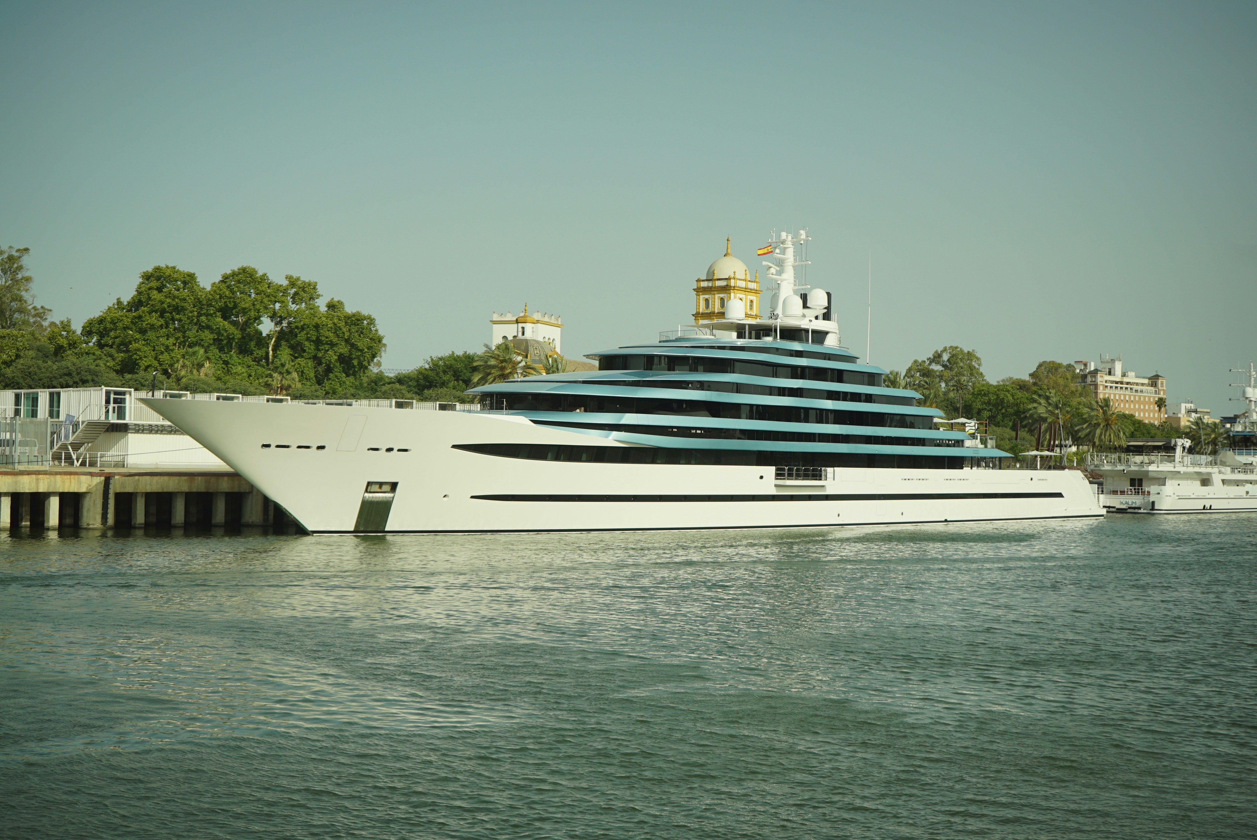Luxurious Offshore Mirage: A Gleaming Superyacht Docked by the Teak-Trimmed Pier