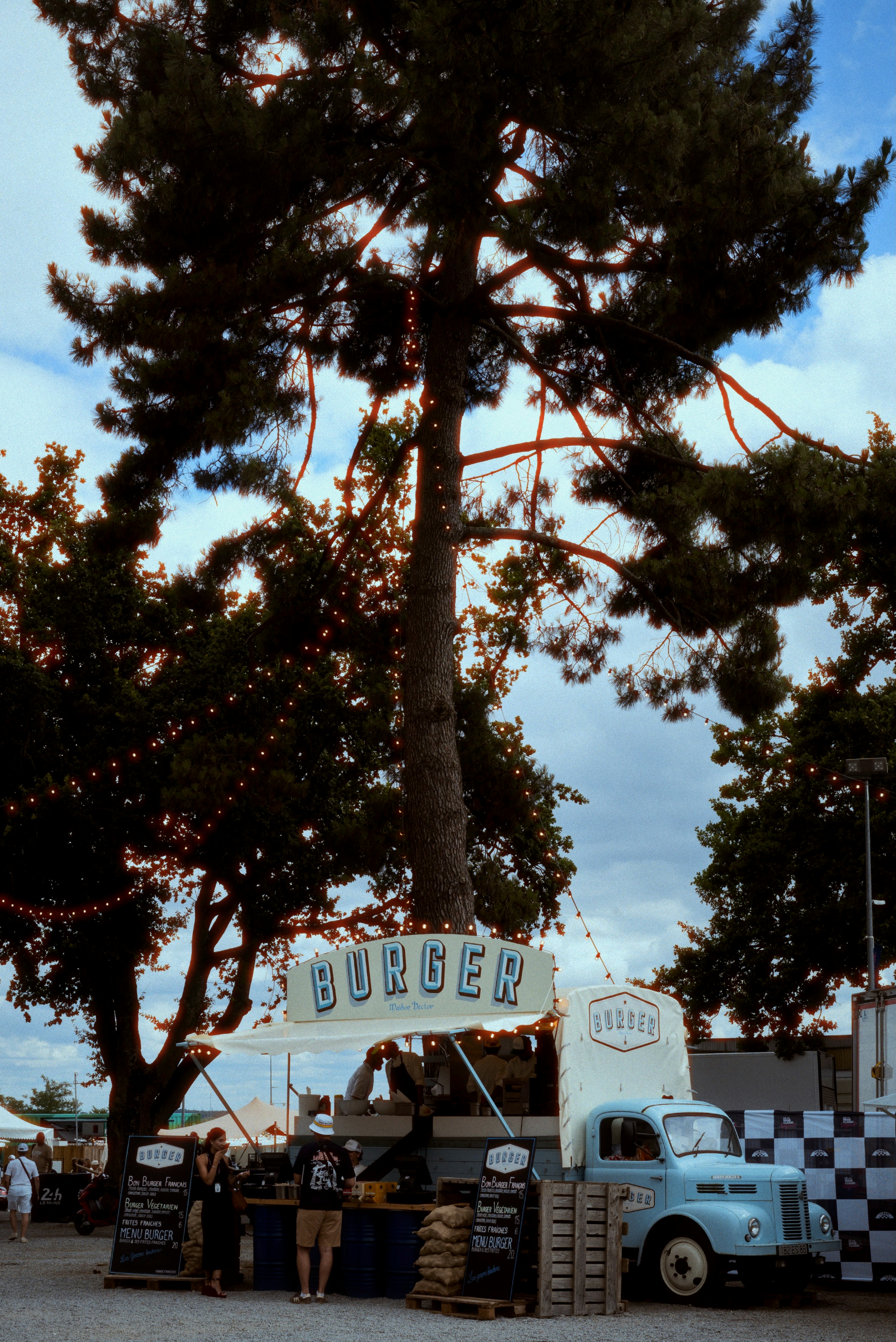 Outdoor burger stand with string lights and vintage truck.