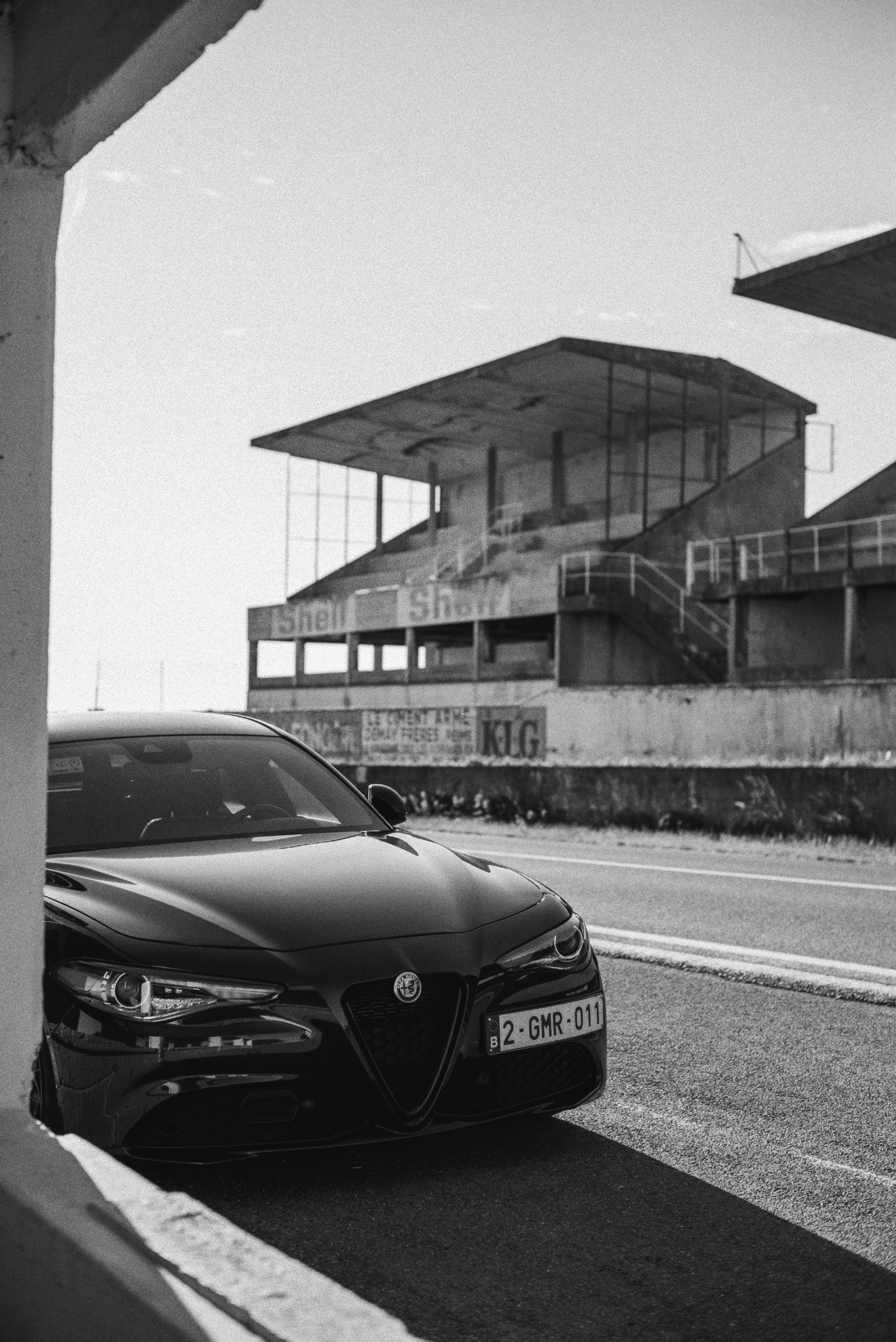 A black car parked near an old race track building.