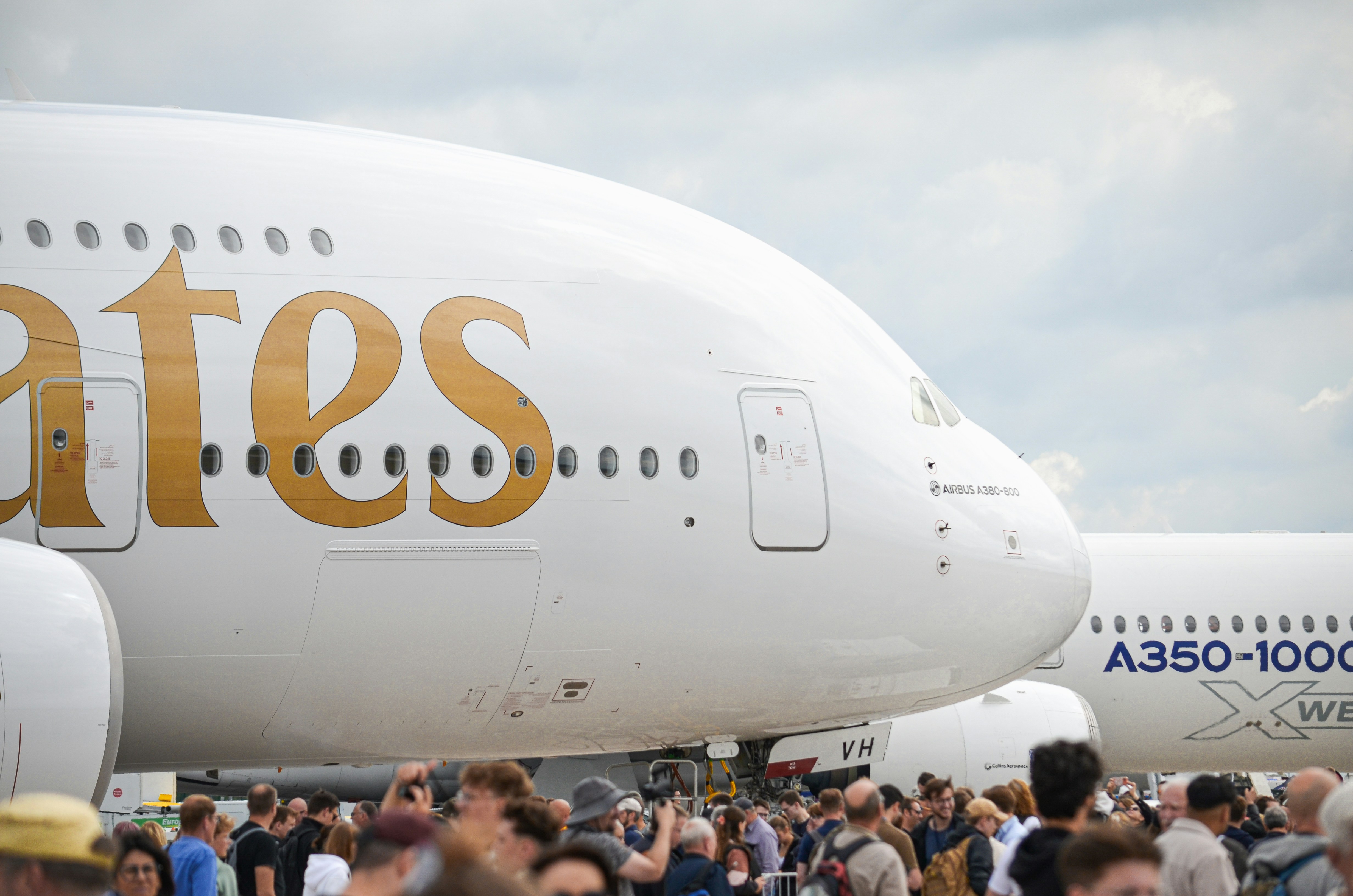 Crowd gathers beneath the nose of a passenger jet during an airshow