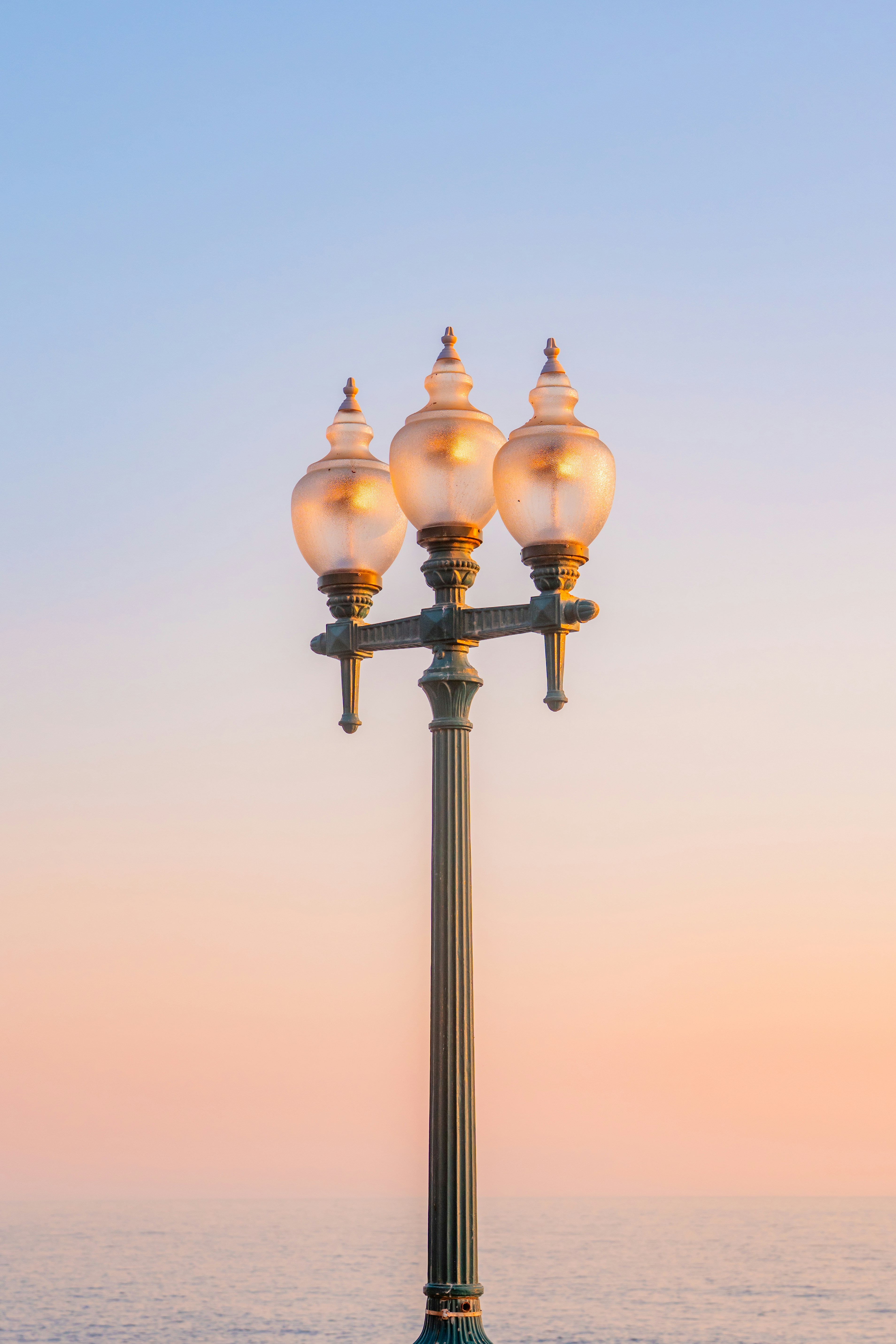 Three-globed Street Lamp at Sunset Over the Water