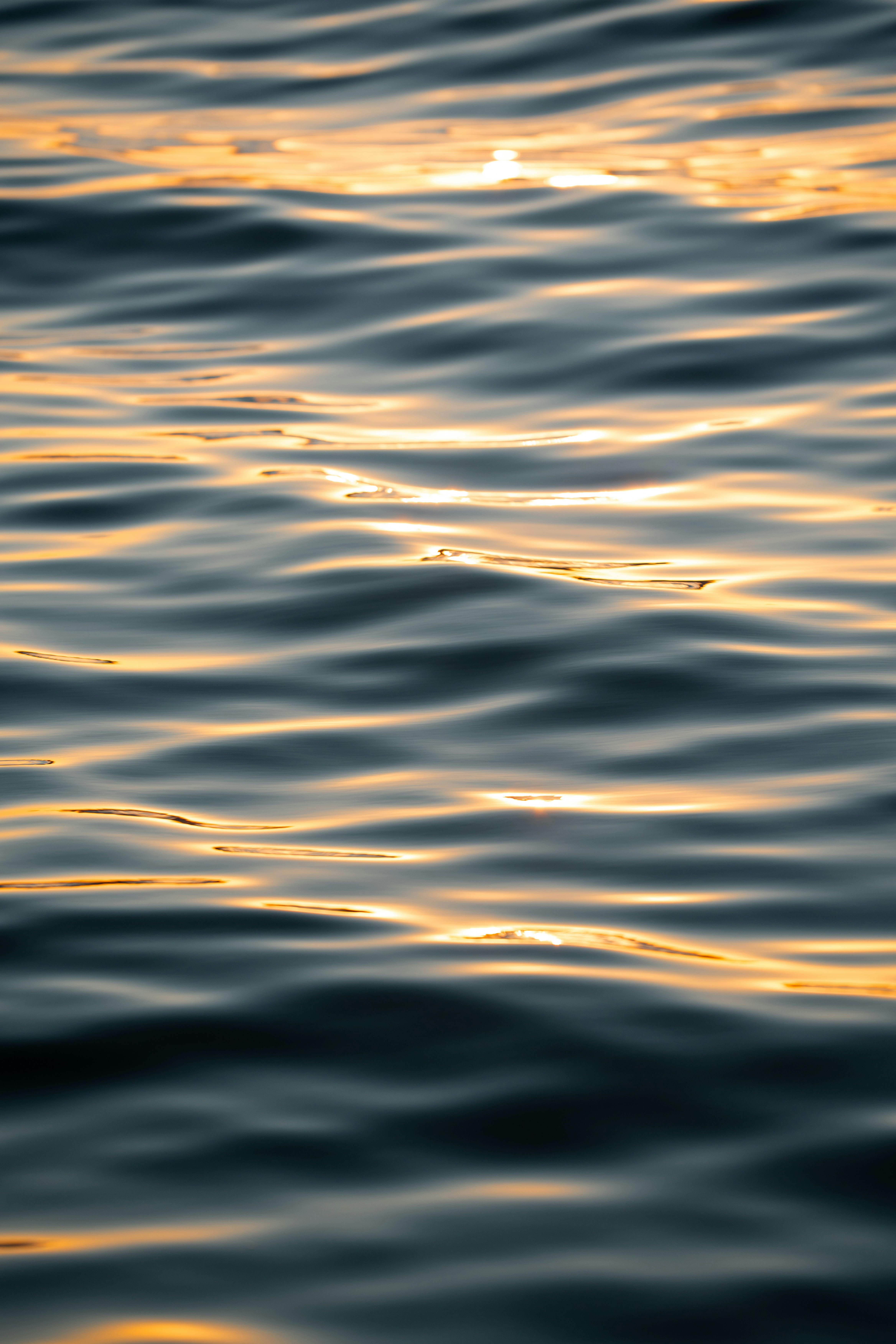 Softly lit water surface with golden highlights and deep blue shadows, captured in a minimal, abstract seascape.