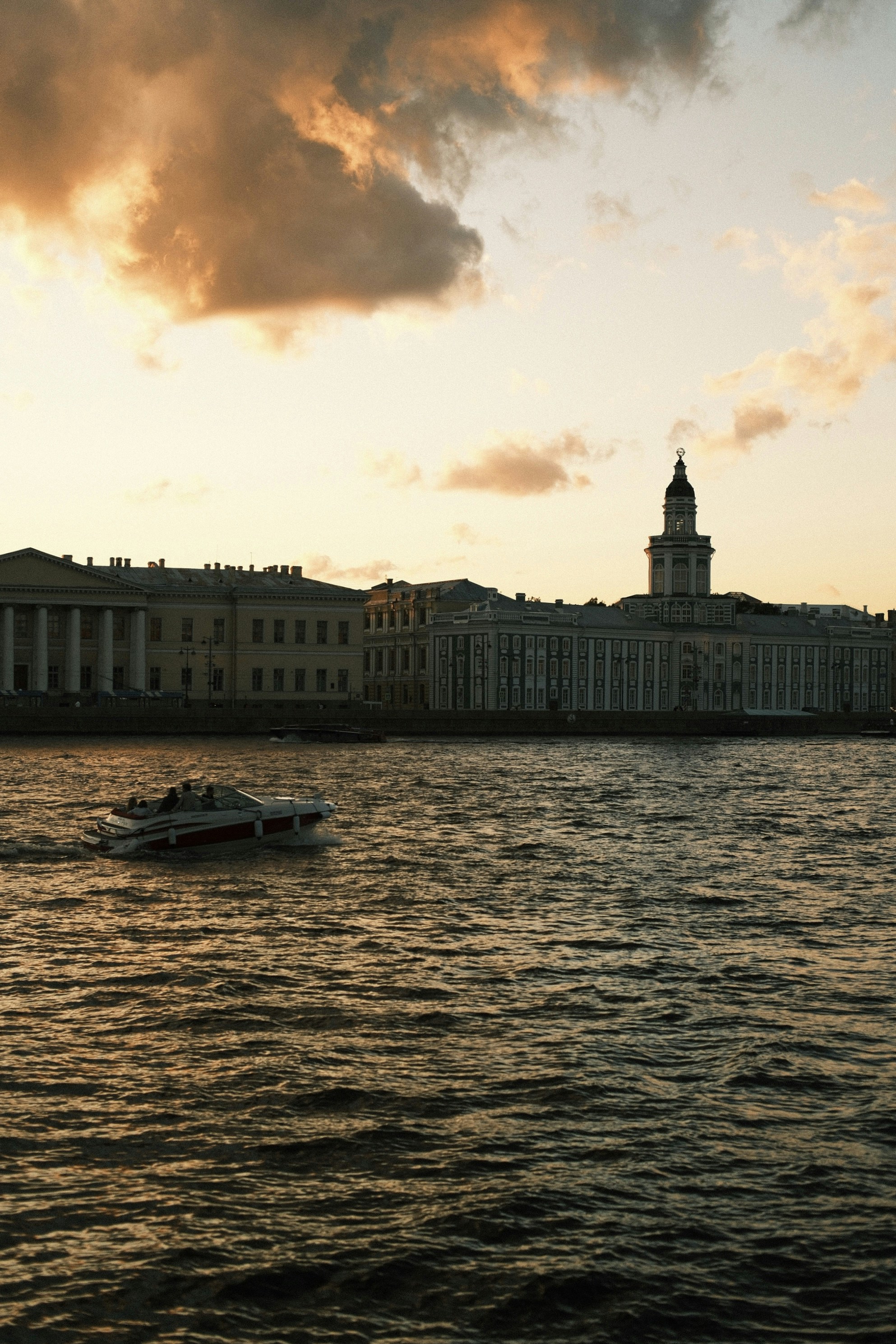 Golden Hour Over the Neva: Boat Meanders Beneath a City Silhouette